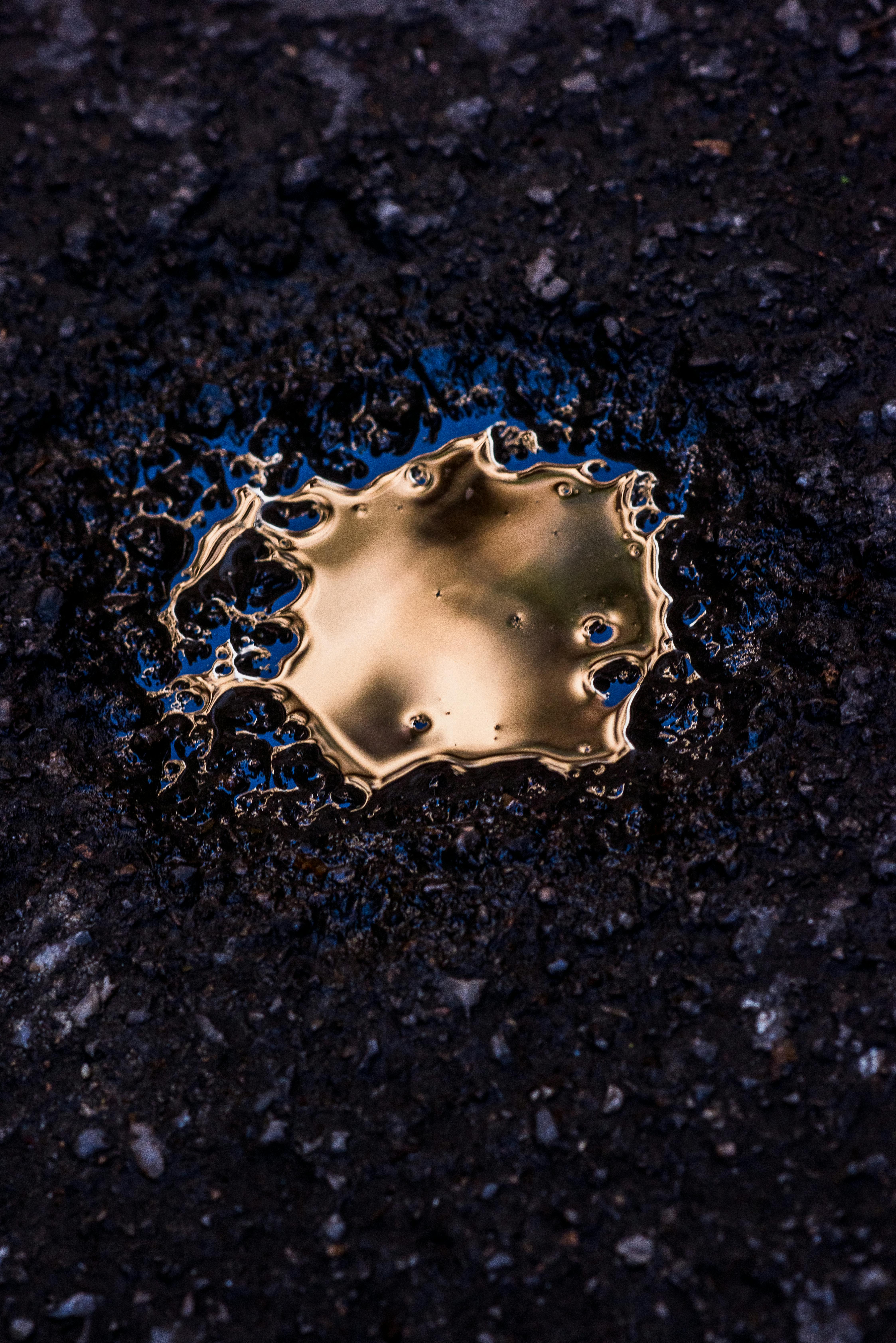 Golden Oil Spill on Dark Asphalt Surface · Free Stock Photo