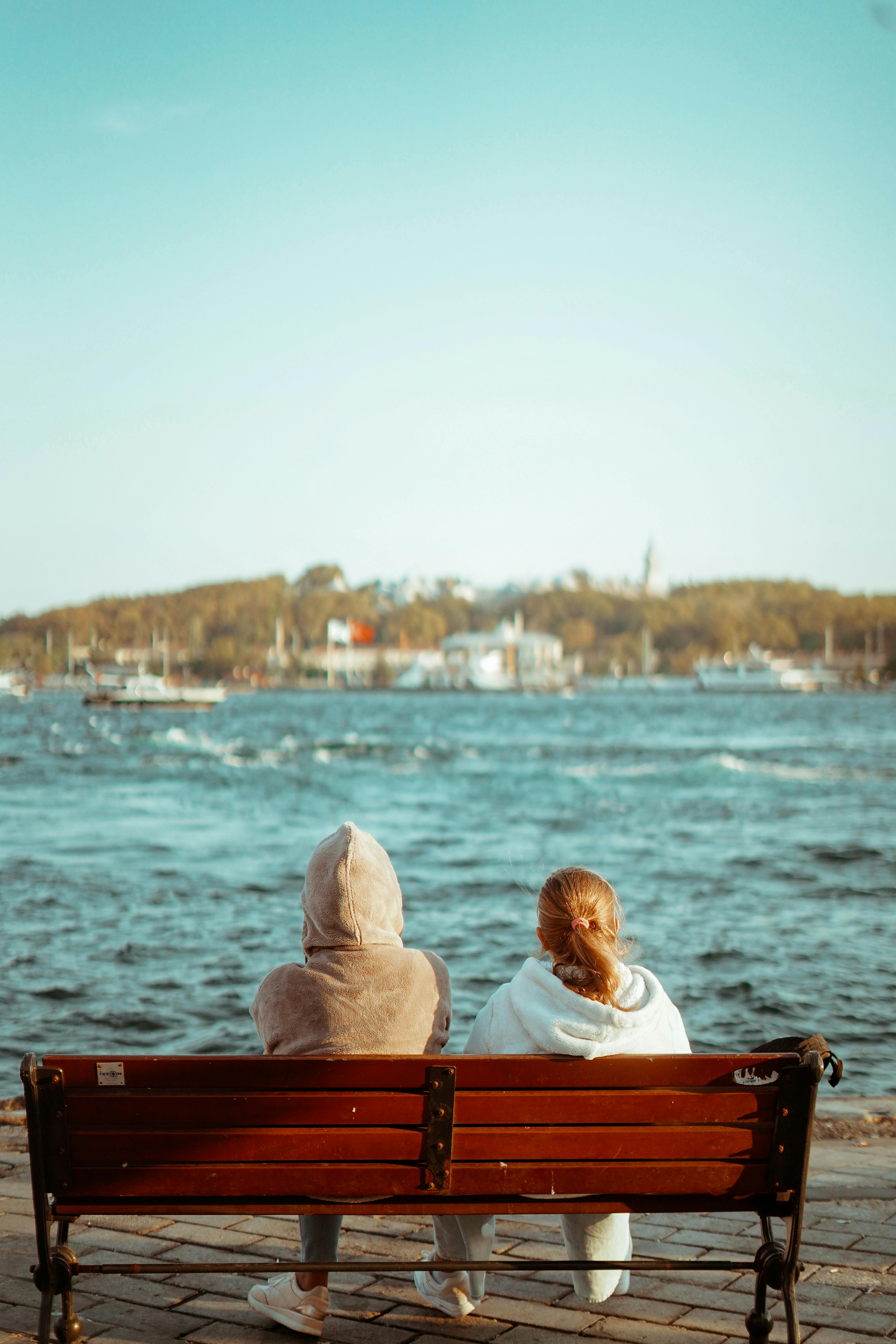 Two People Relaxing by the Waterfront in Autumn · Free Stock Photo
