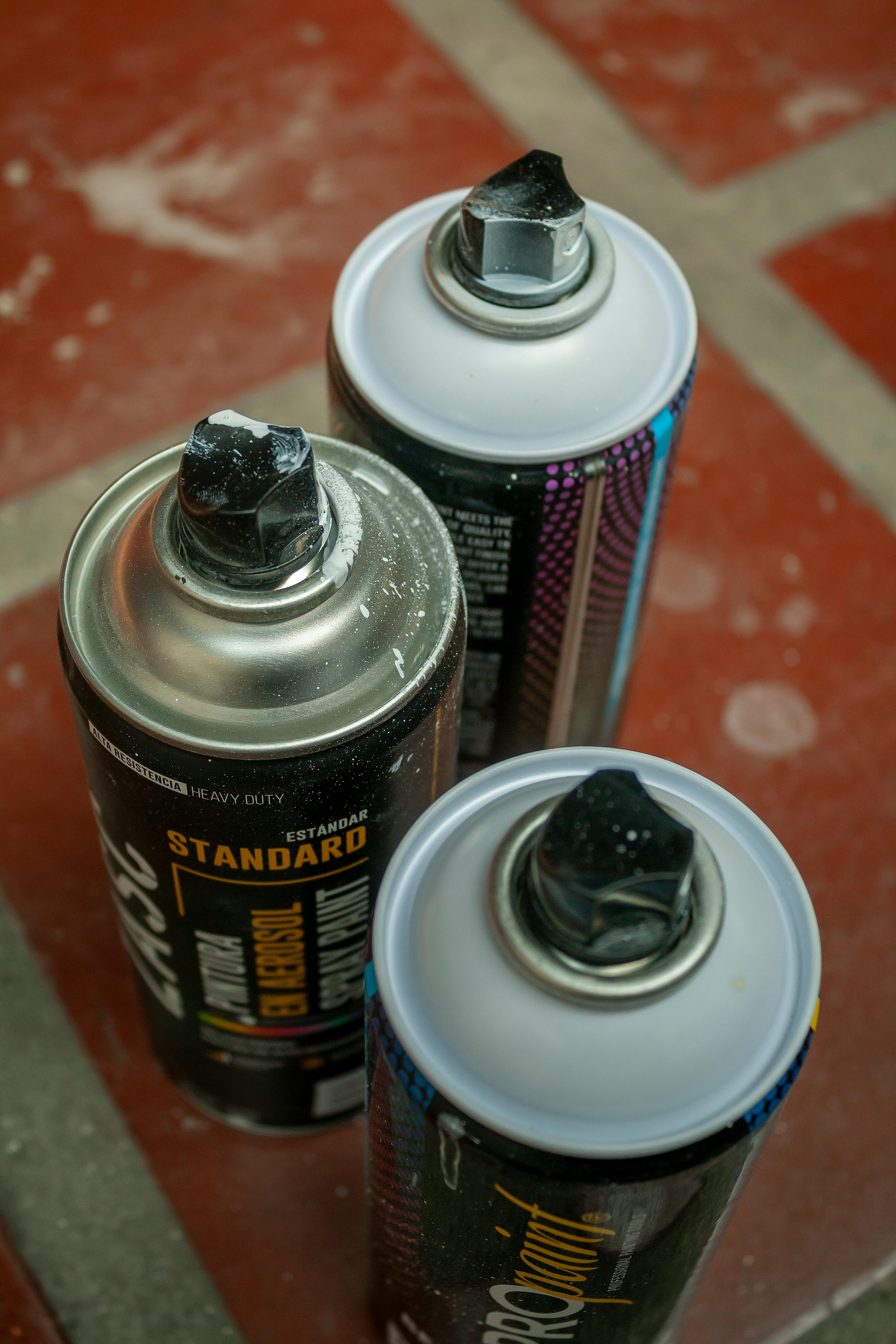 Spray Paint Cans on Tiled Outdoor Surface · Free Stock Photo