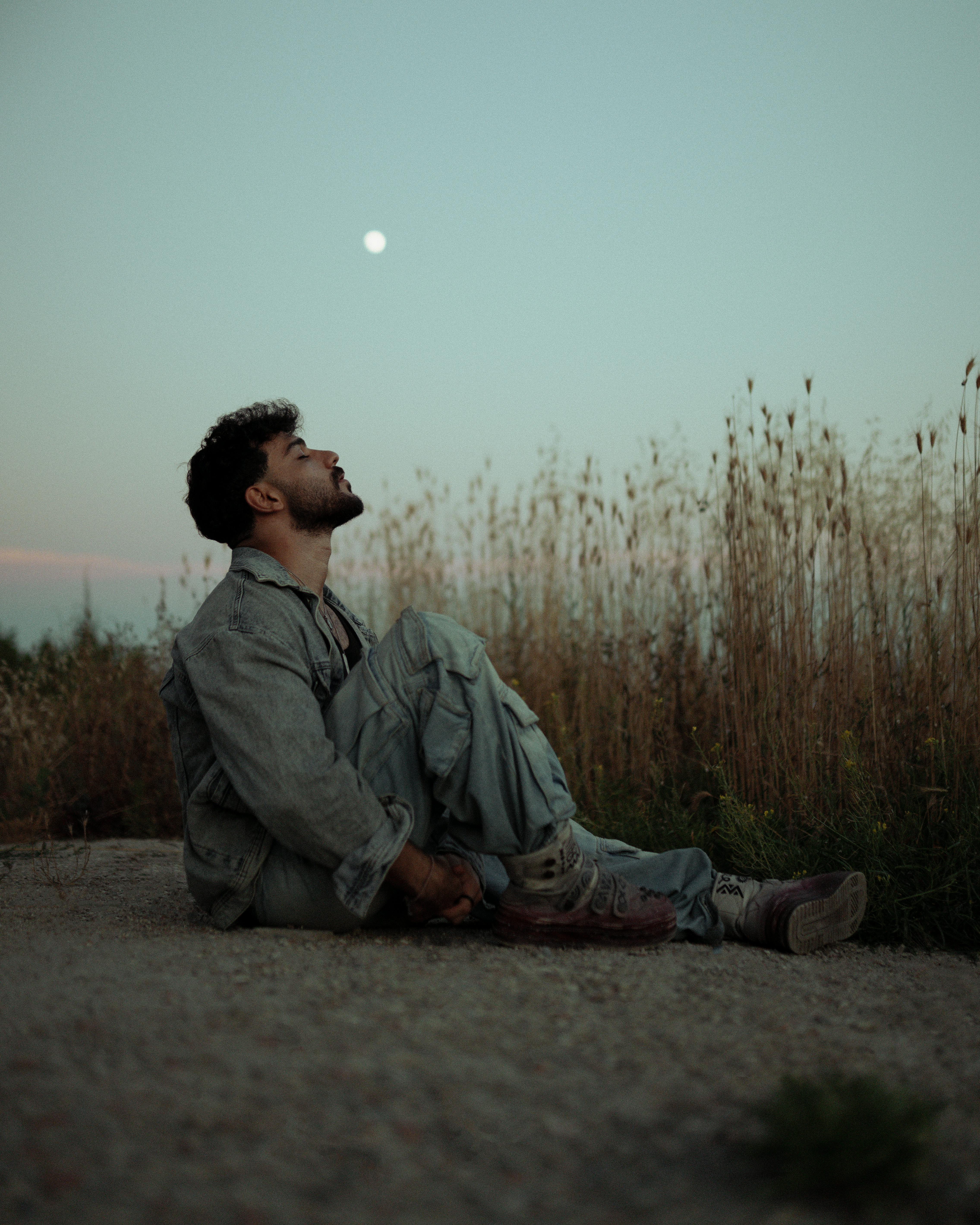 Reflective Man Sitting Outdoors at Twilight · Free Stock Photo