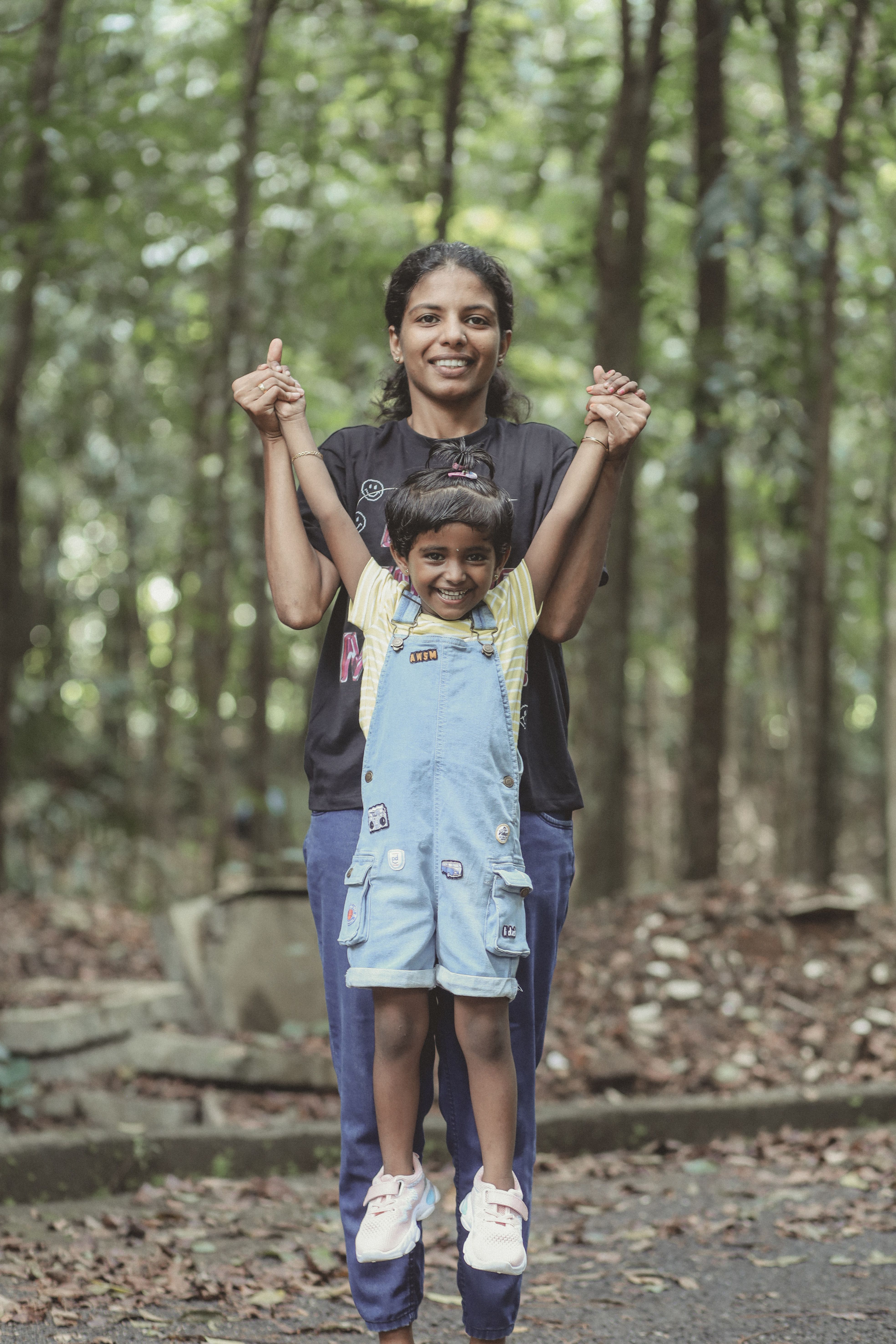 Mother Lifting Child in Forest Setting · Free Stock Photo