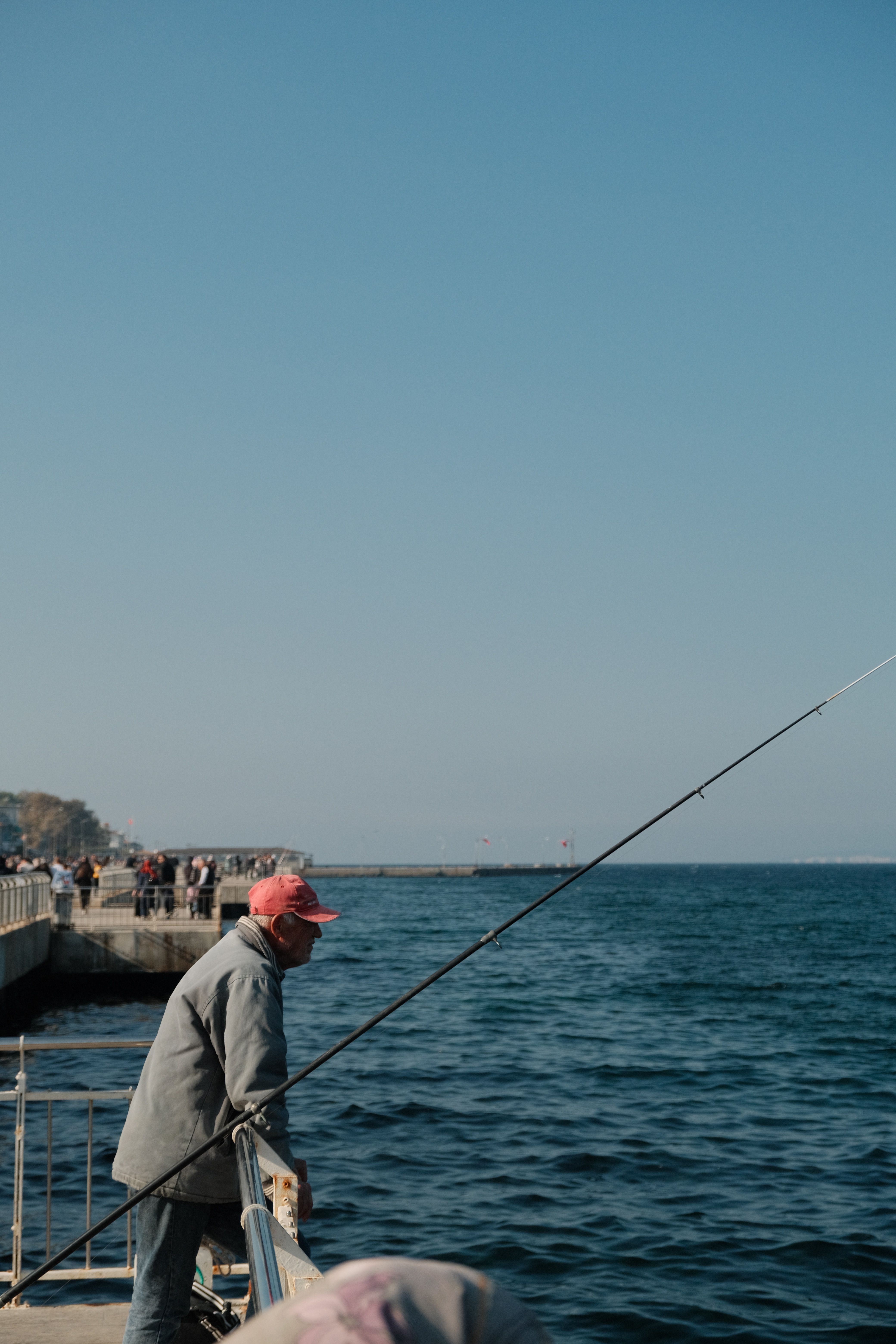 Man Fishing off a Pier on a Clear Day · Free Stock Photo