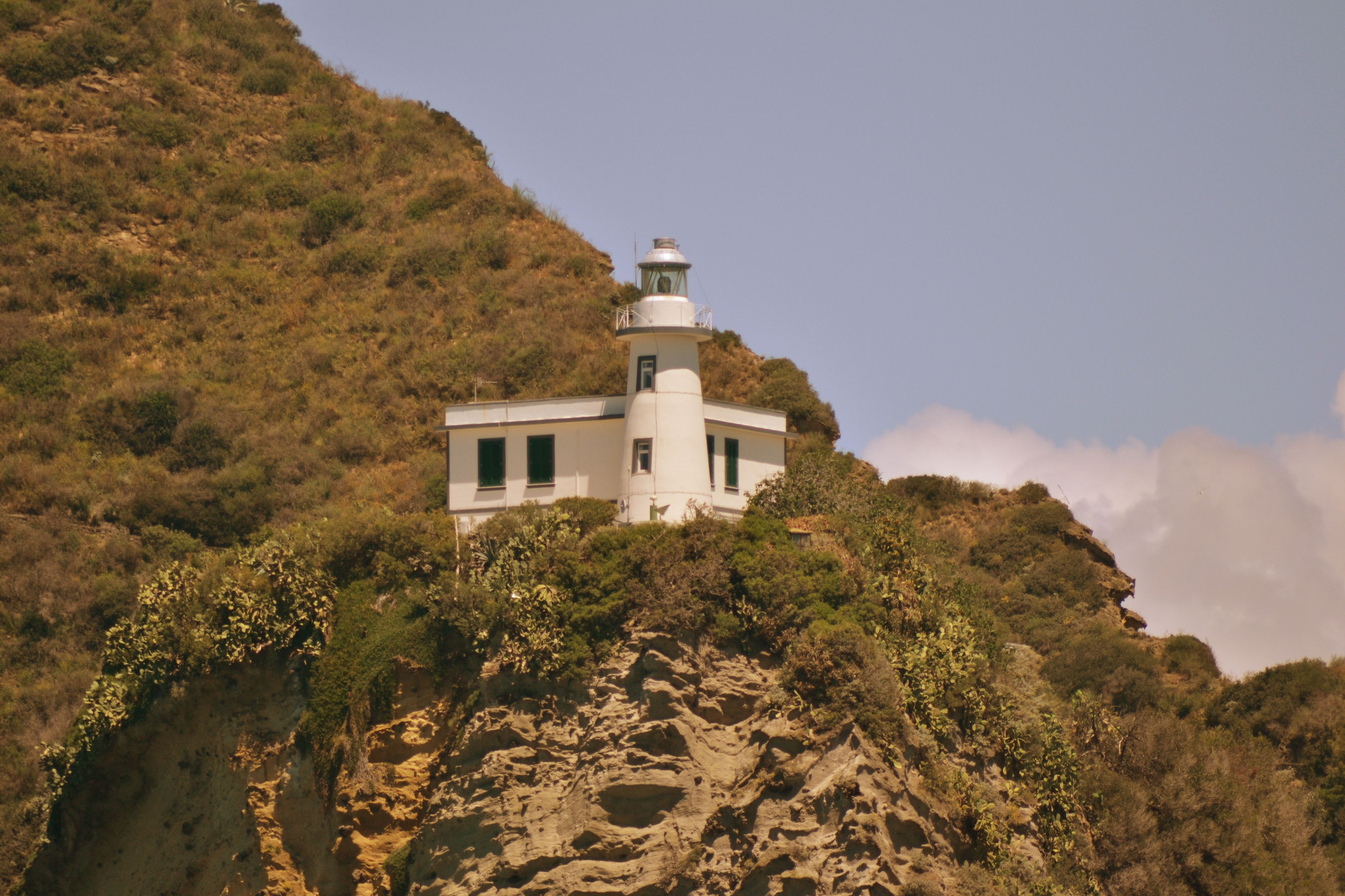 Scenic Lighthouse on Rocky Cliff Under Blue Sky · Free Stock Photo