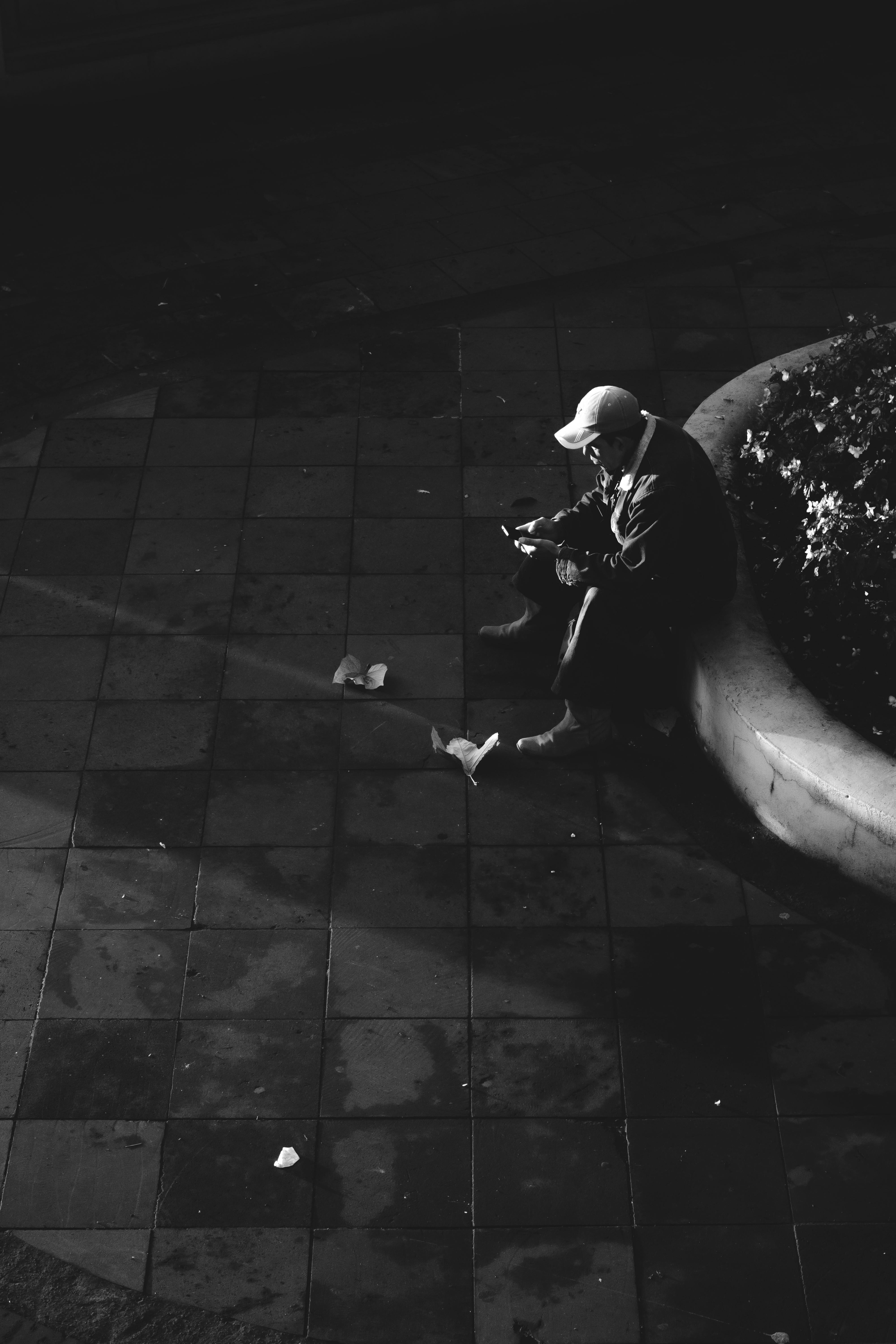 Lonely Man Sitting in Shadows on Pavement · Free Stock Photo