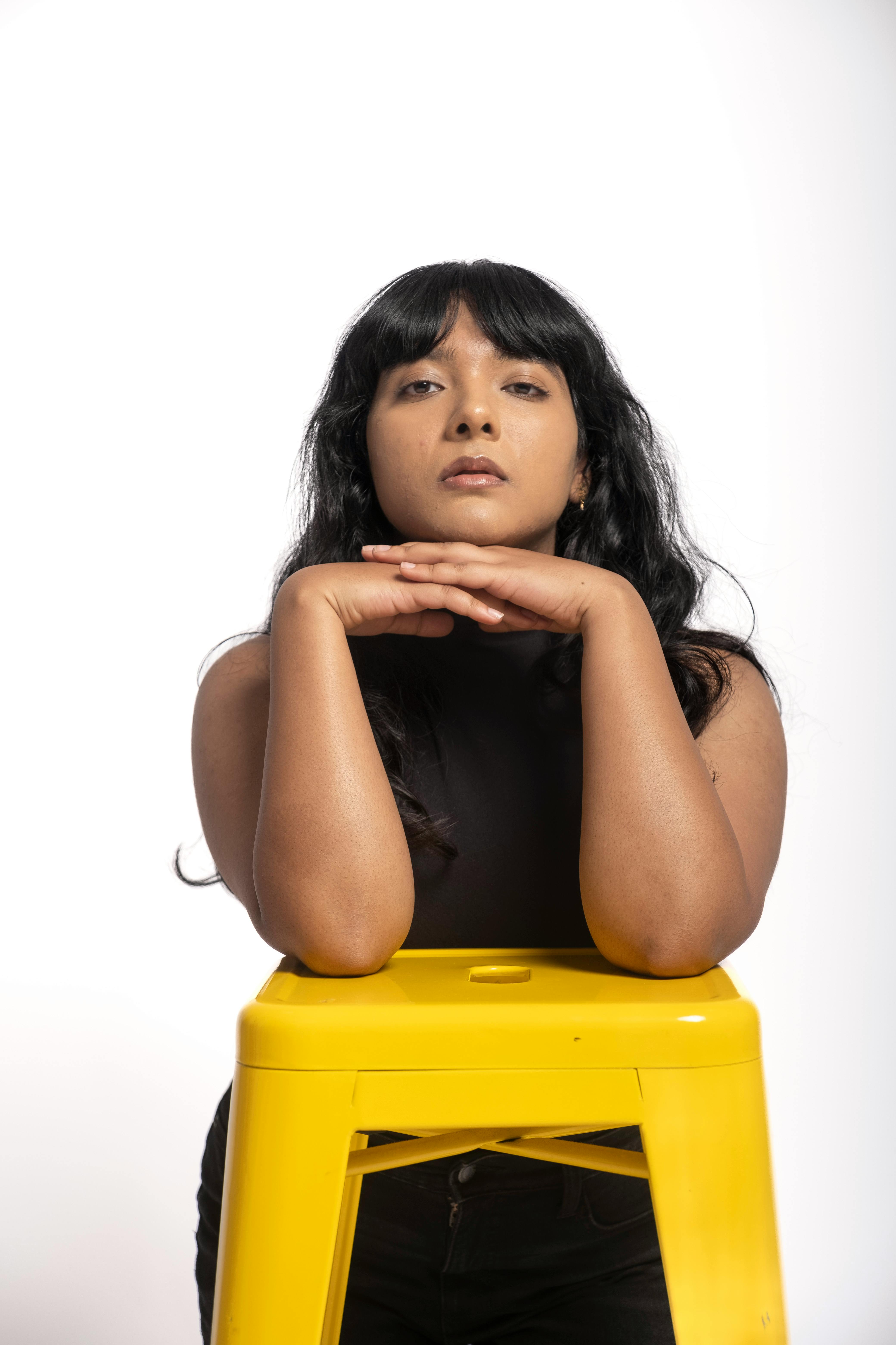 Portrait of a Woman Leaning on Yellow Stool · Free Stock Photo