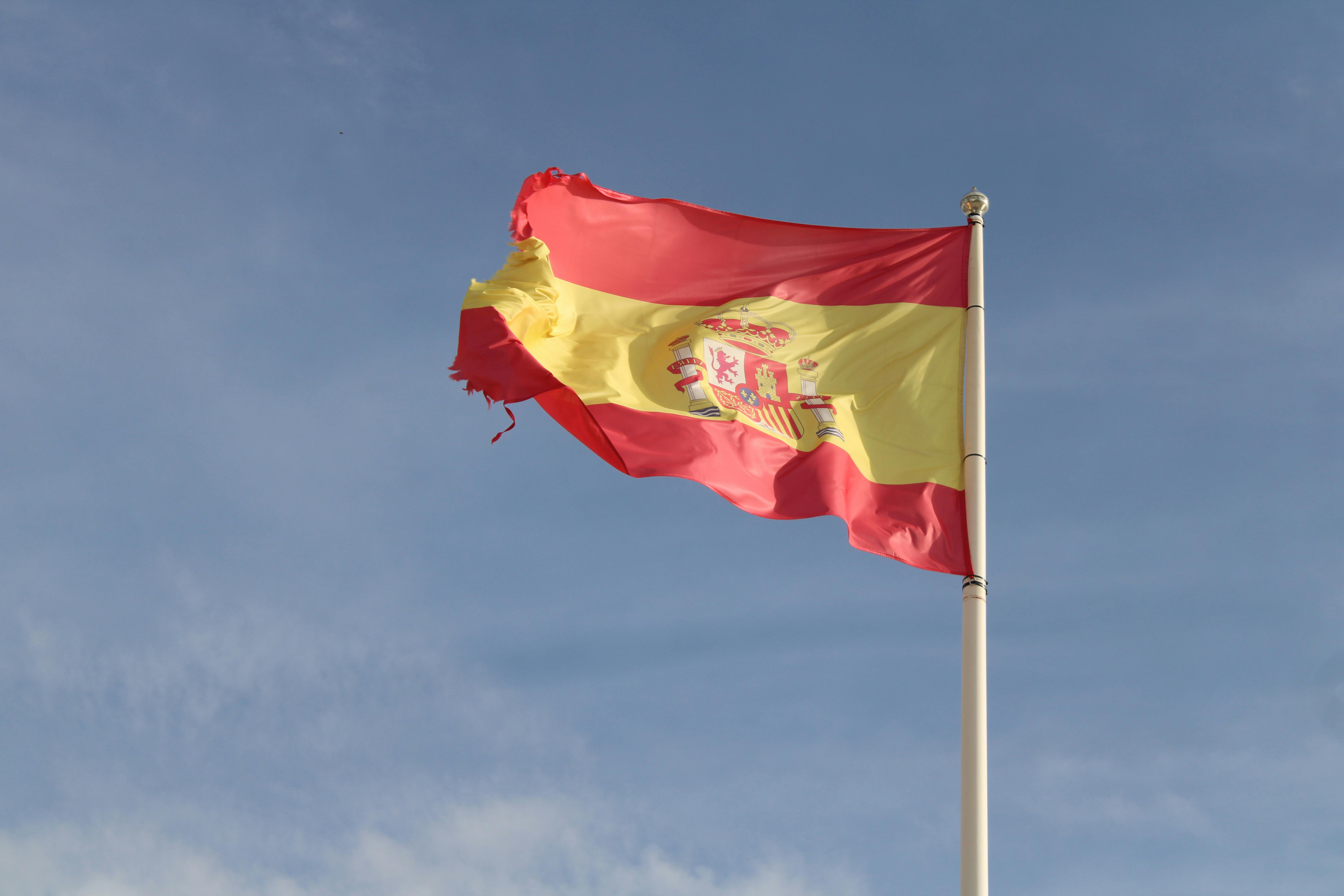 Spanish Flag Waving in Blue Sky · Free Stock Photo