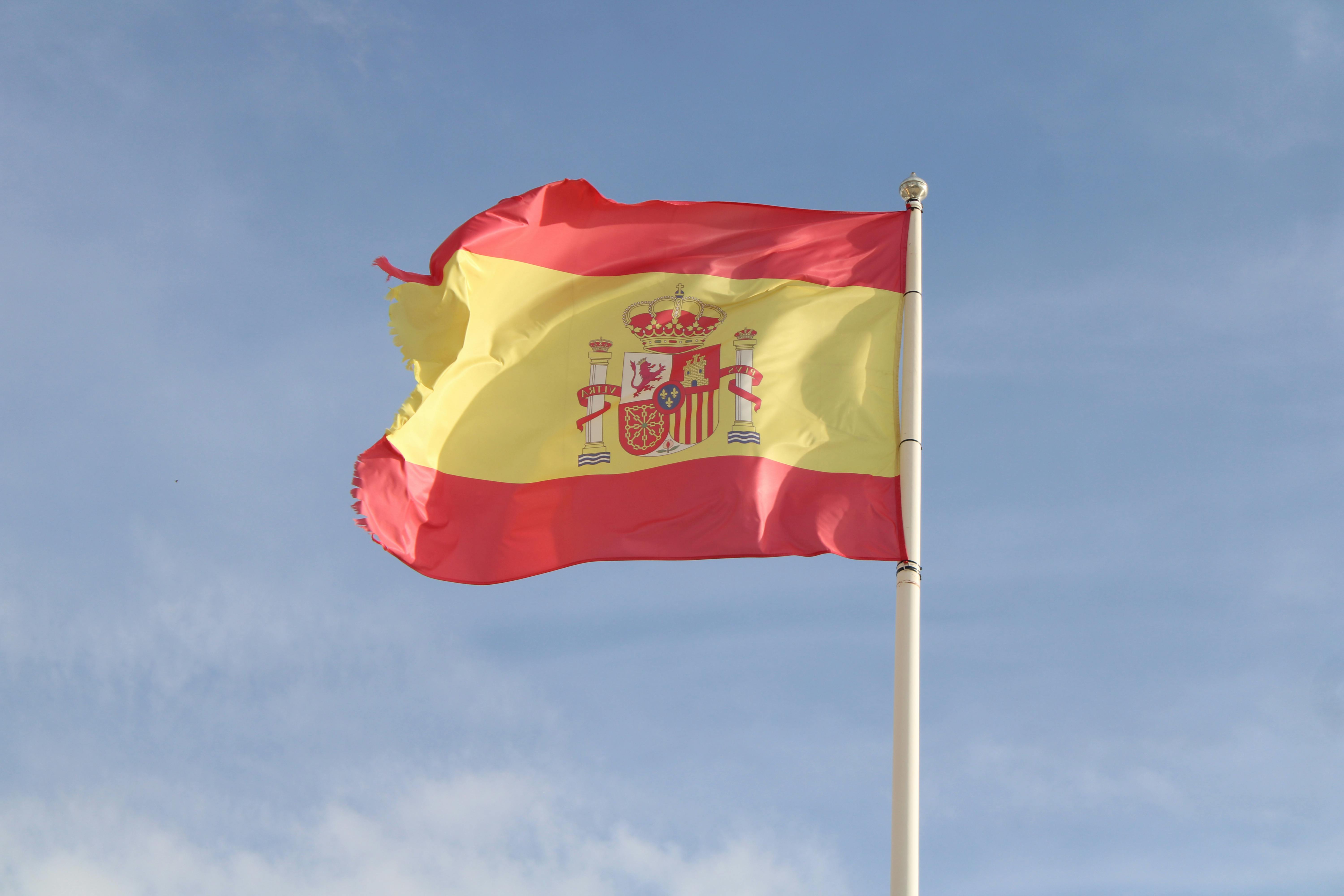Spanish National Flag Waving Against Blue Sky · Free Stock Photo