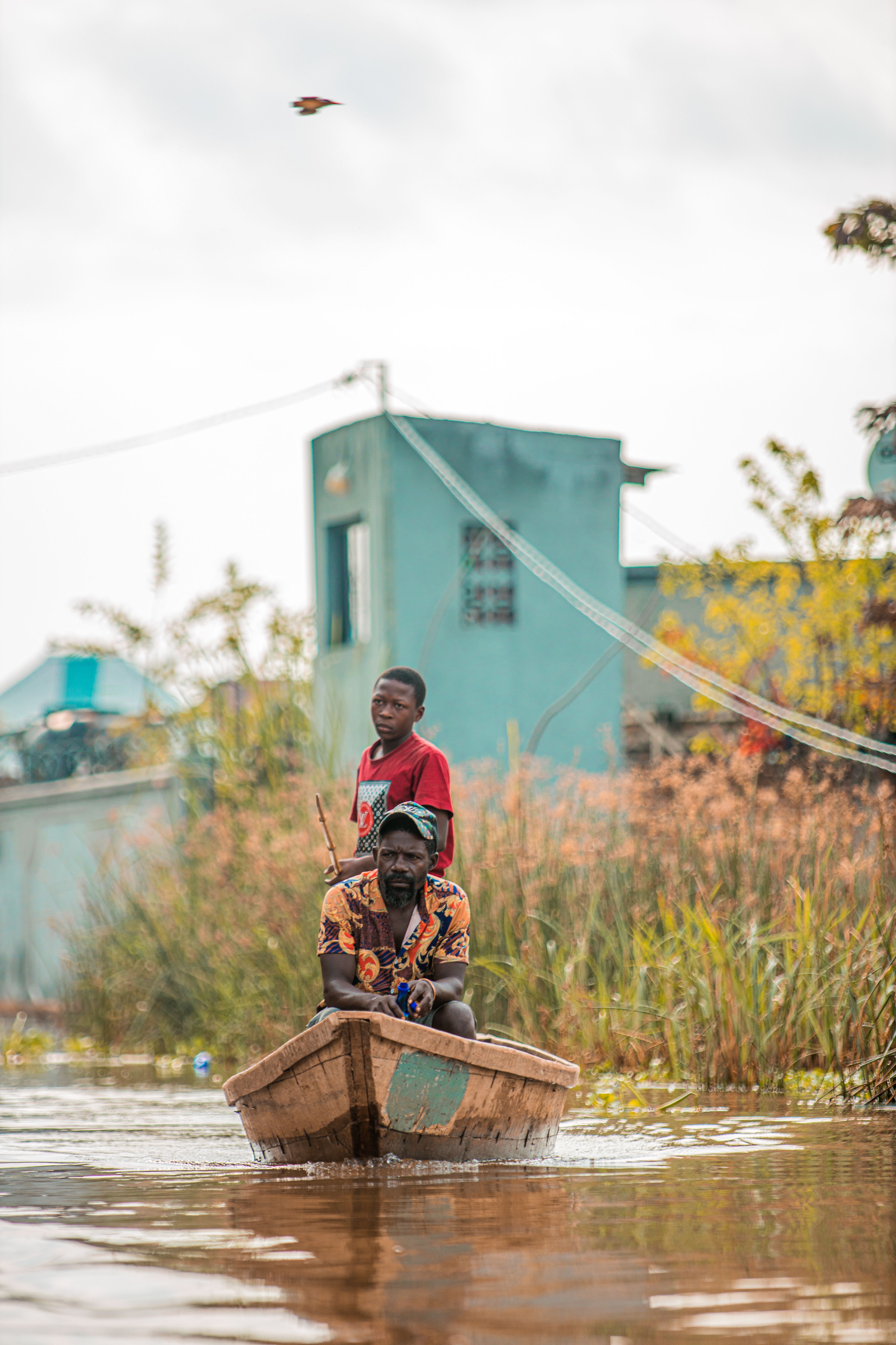 Two Men Navigating a Small Boat in a River · Free Stock Photo