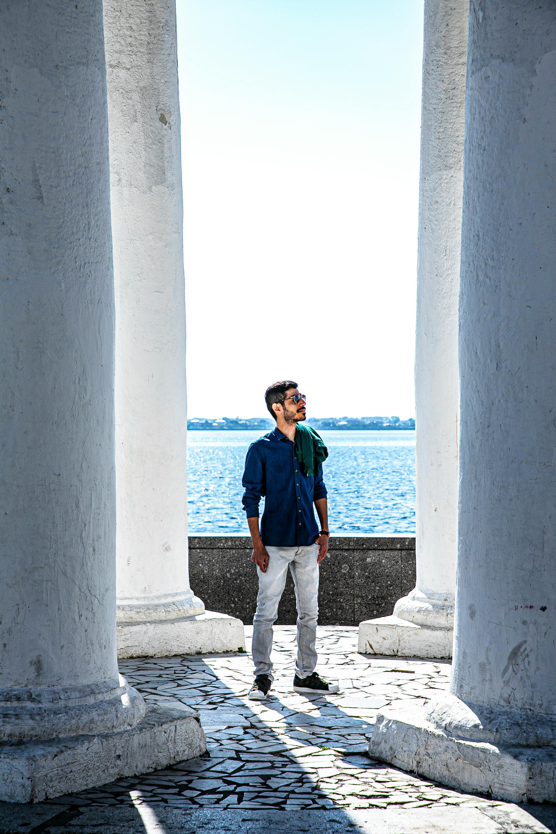 Man in standing between columns on embankment · Free Stock Photo