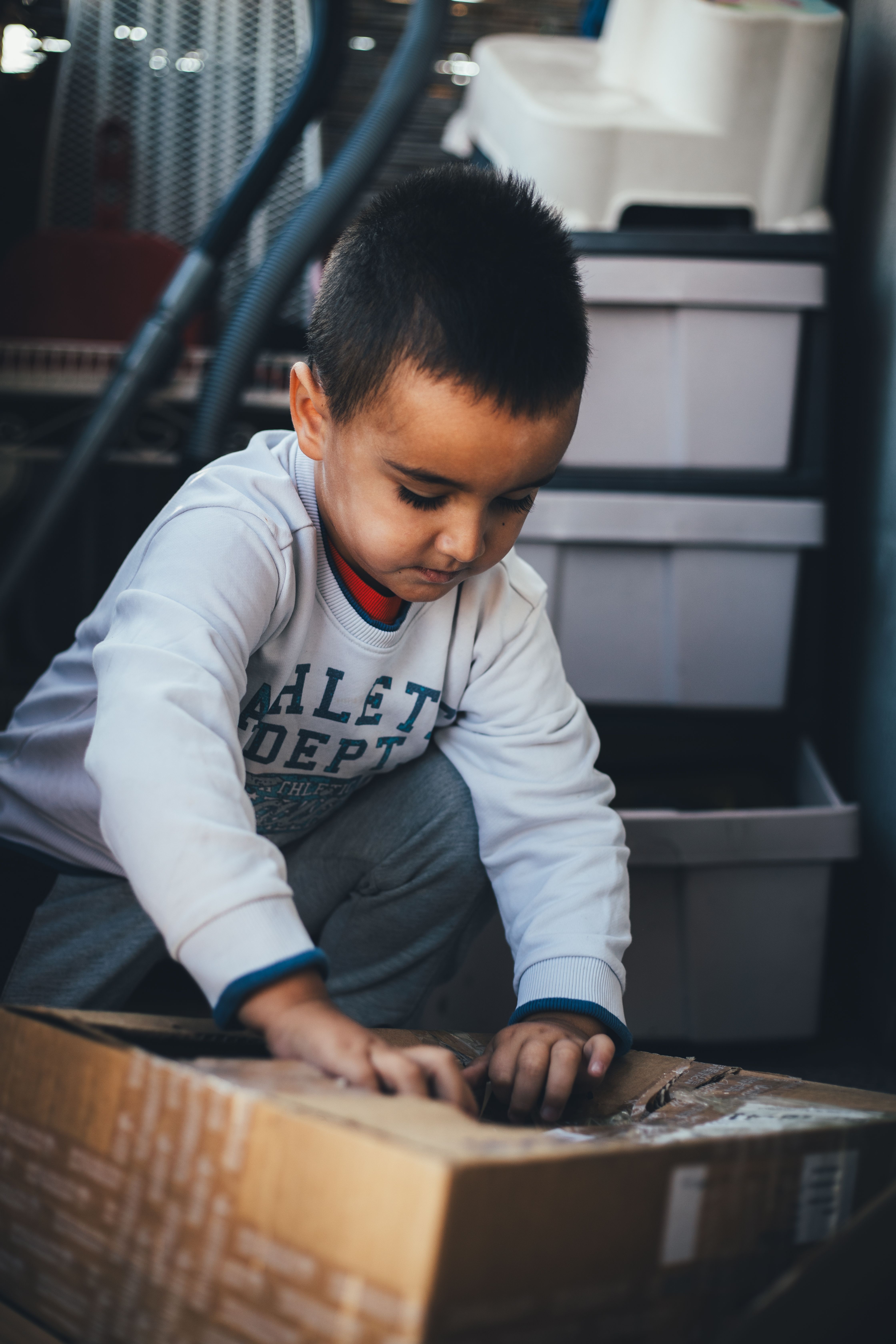 Young Boy Exploring Cardboard Box Indoors · Free Stock Photo