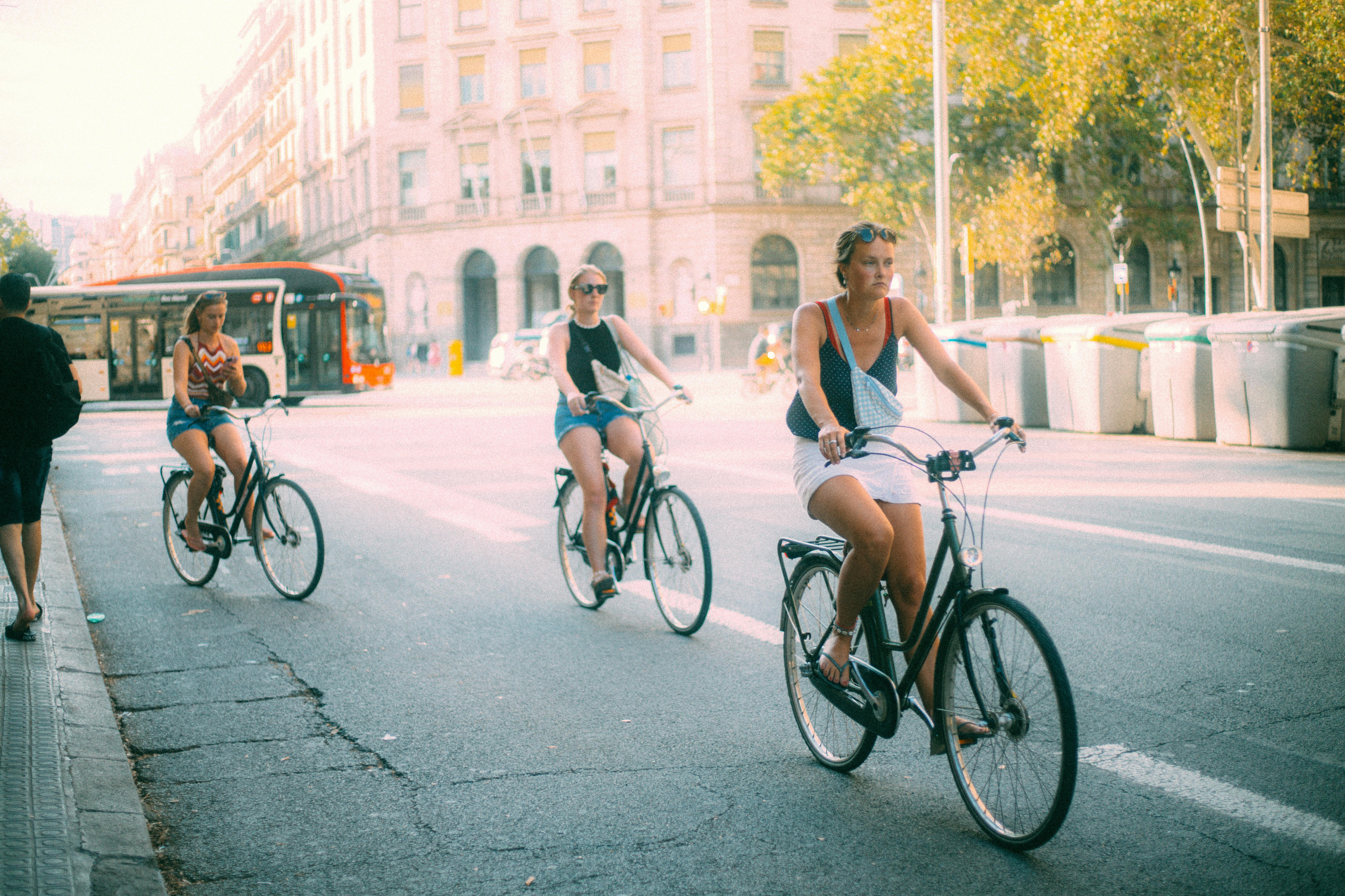 Three Women Biking on Sunny Urban Street · Free Stock Photo