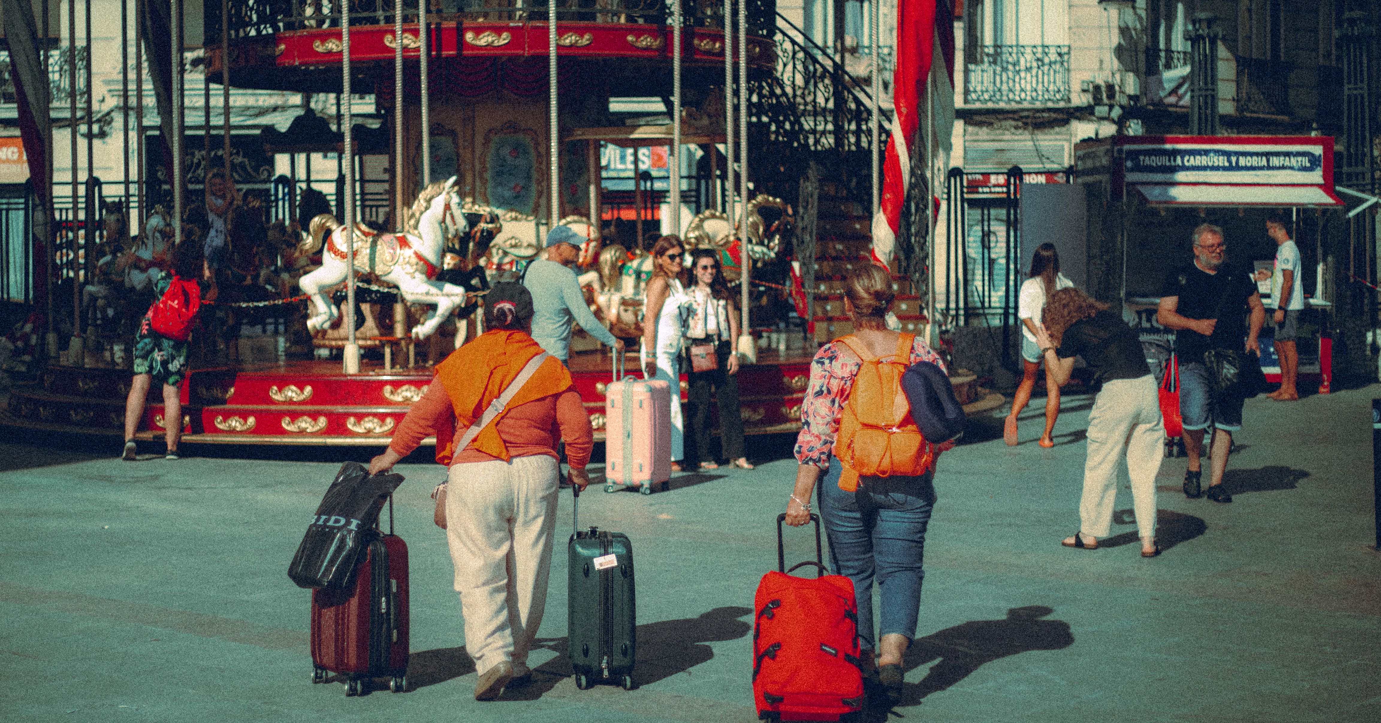 Tourists with Luggage Near Carousel in City Park · Free Stock Photo