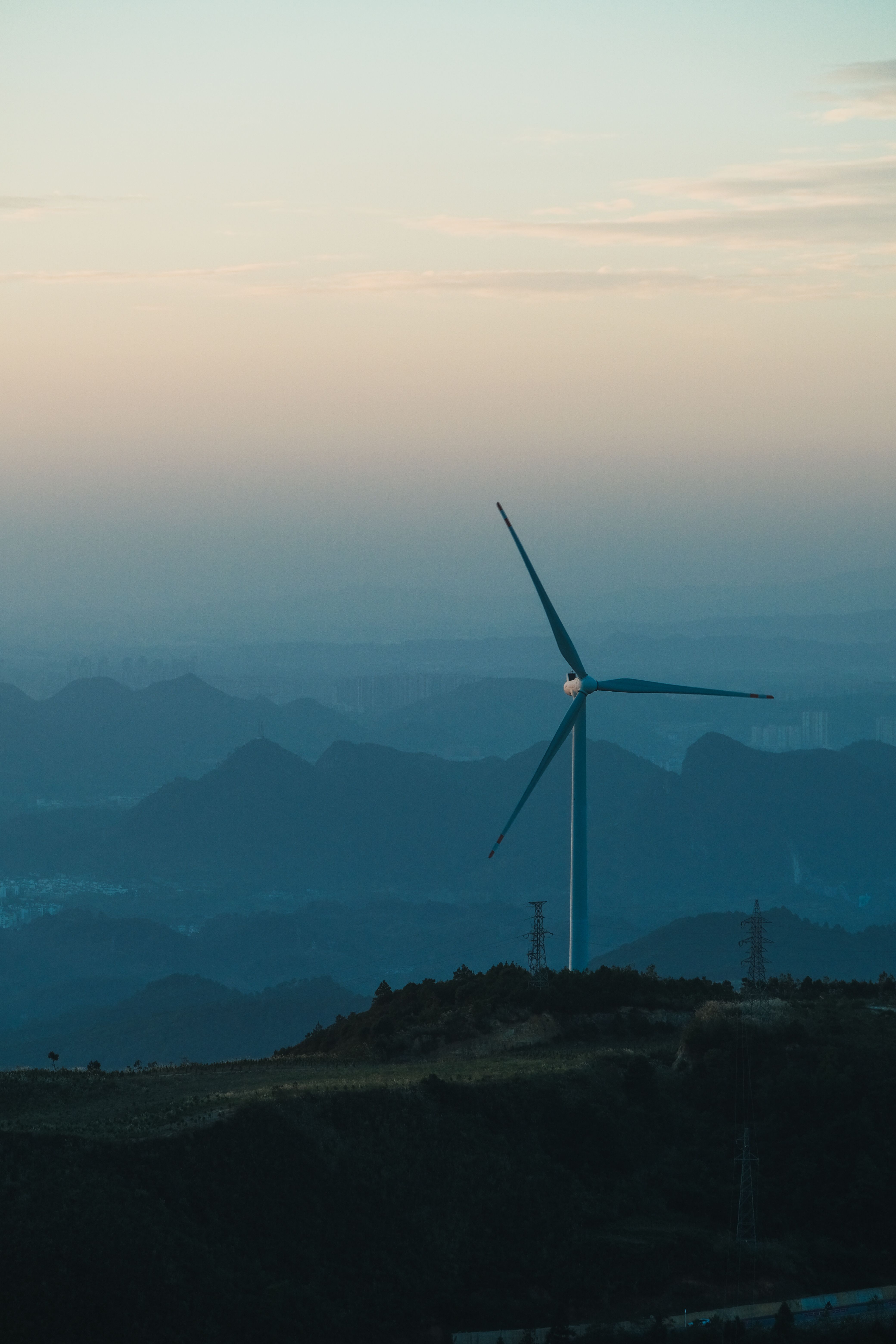 Wind Turbine at Sunset Over Hazy Mountains · Free Stock Photo