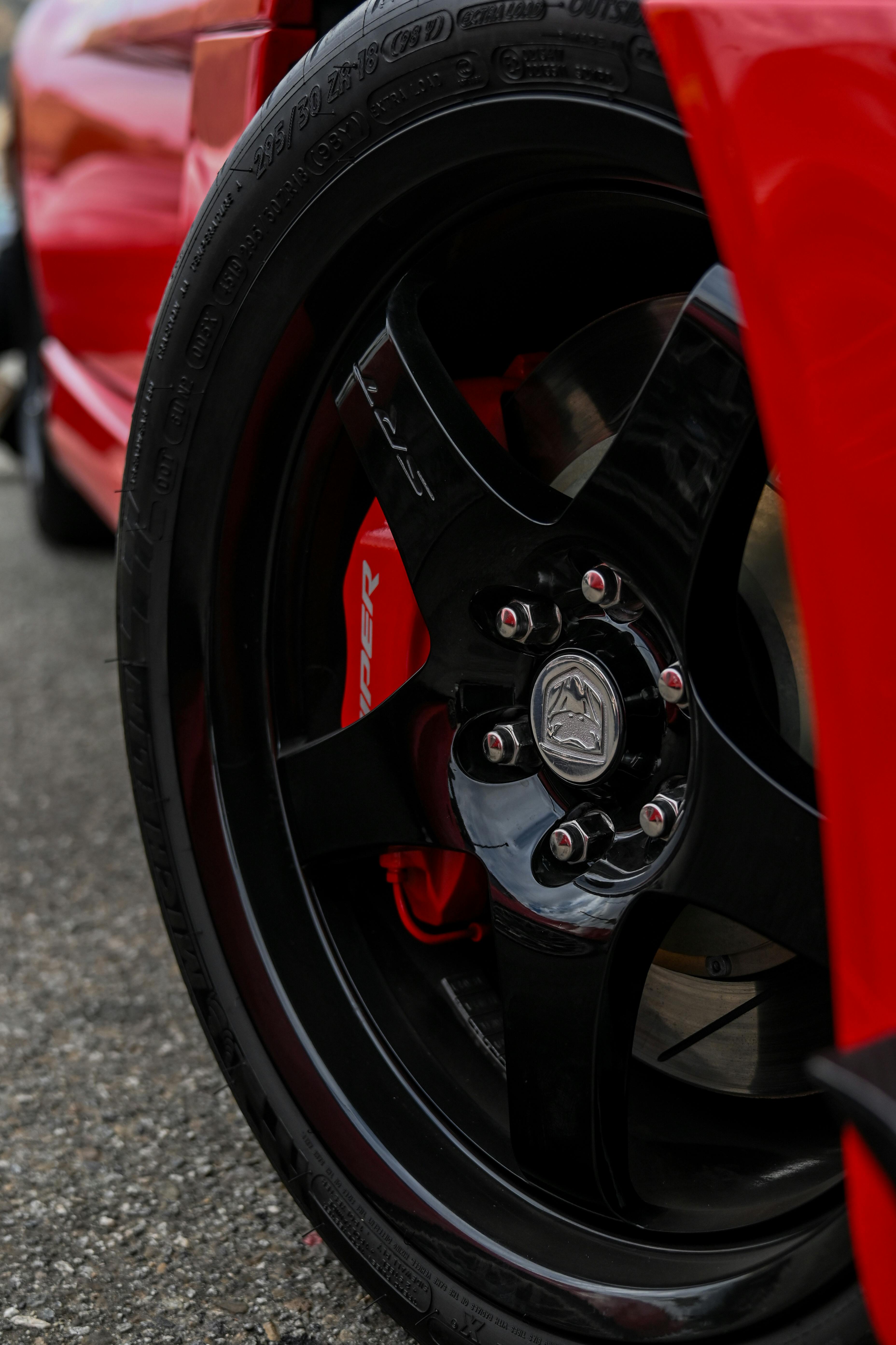 Close-Up of Sporty Red Car Wheel with Logo · Free Stock Photo
