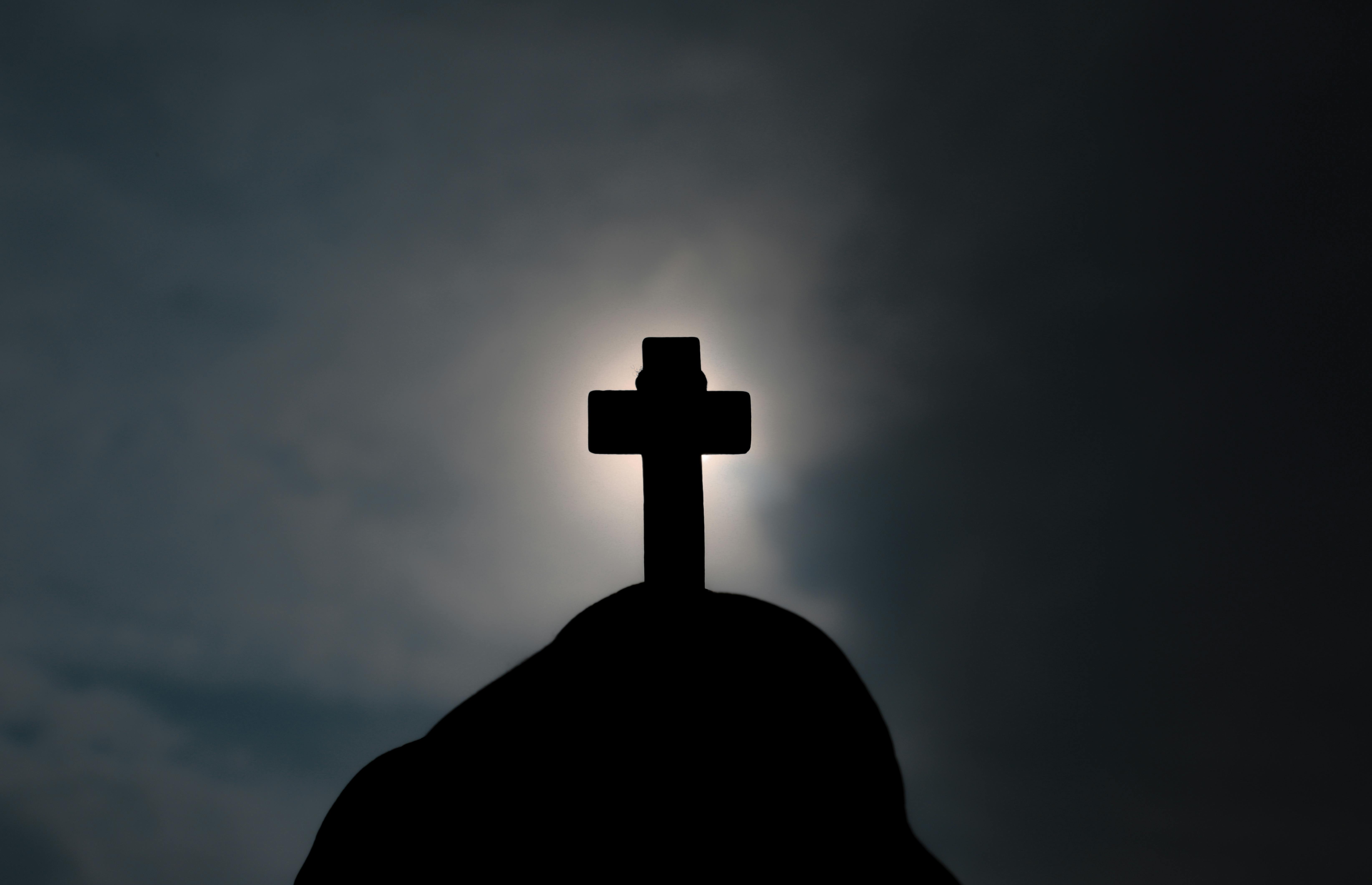 Foto profissional gratuita de braços cruzados, cruz, lindo pôr do sol