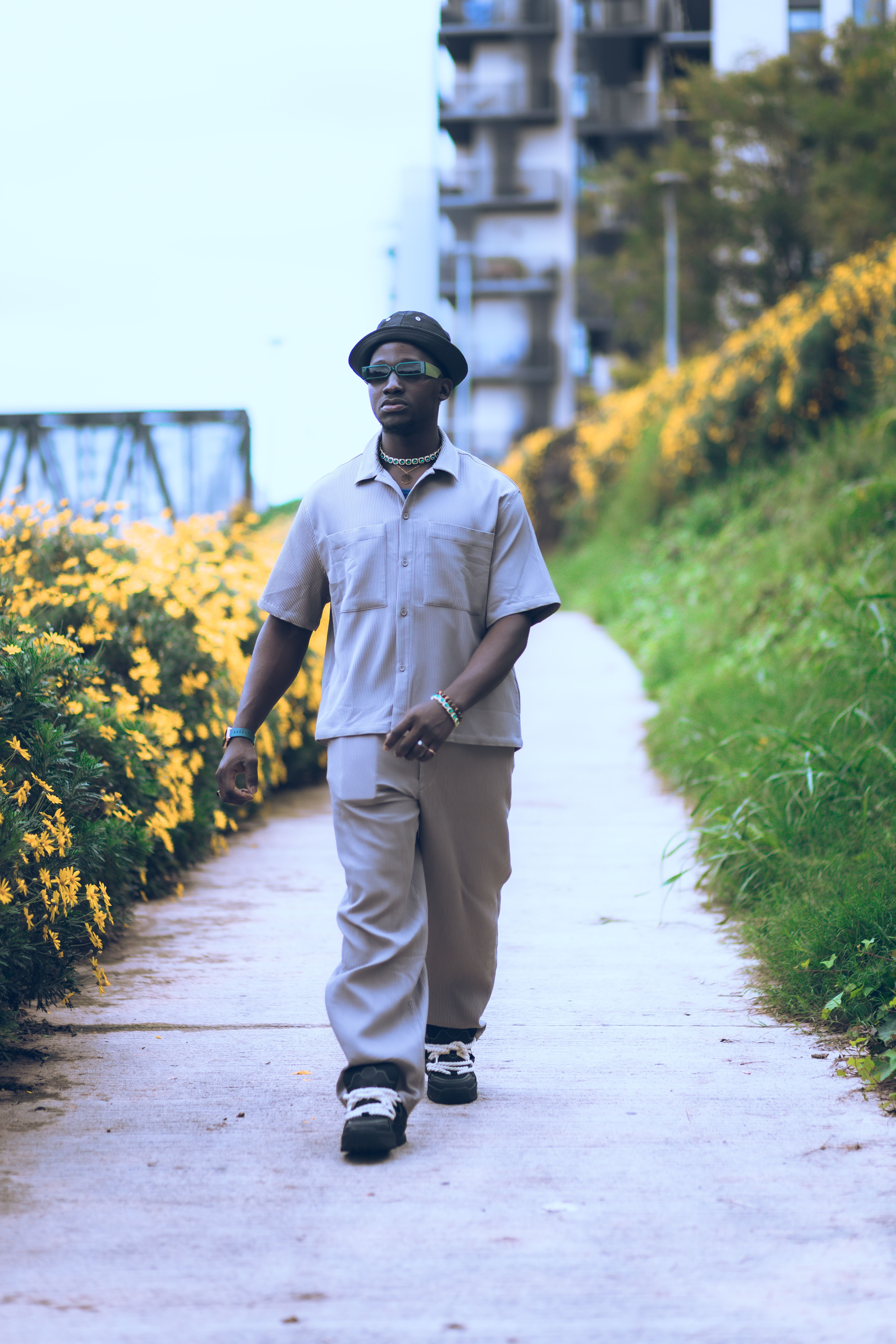 Stylish Man Walking on Flower-lined Path Outdoors · Free Stock Photo
