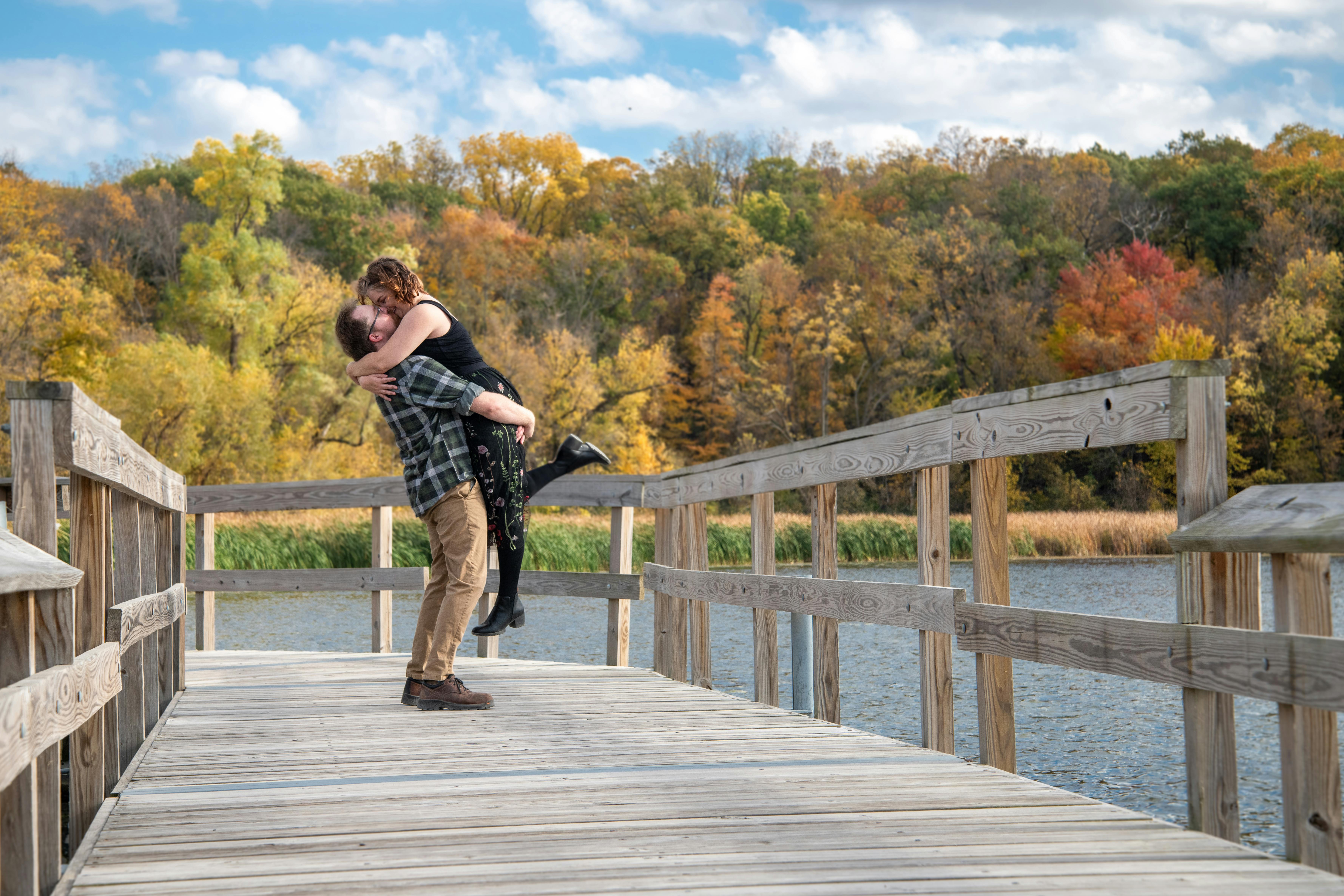 Romantic Couple Embracing on Scenic Autumn Dock · Free Stock Photo