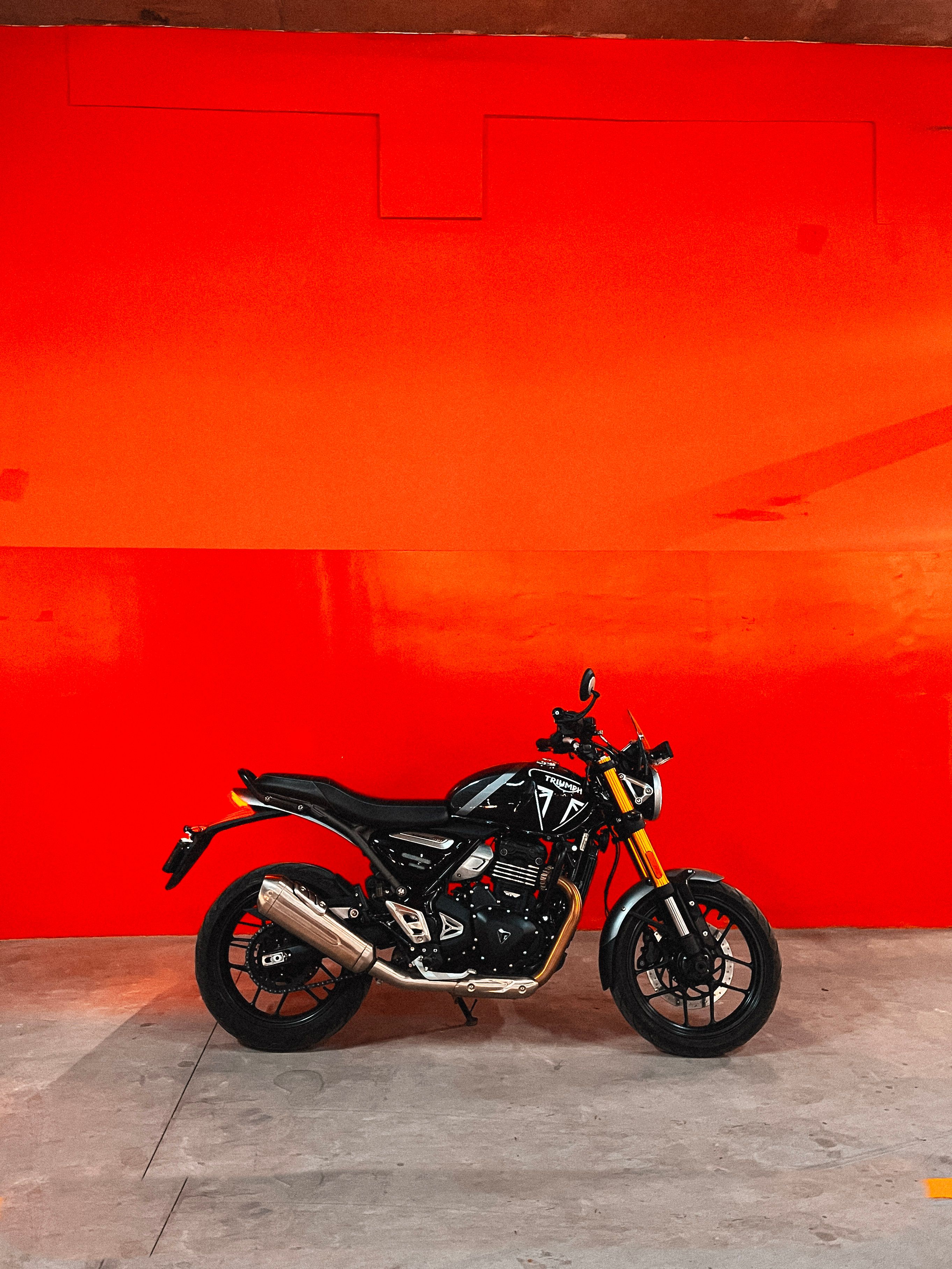 Classic Black Motorcycle Against Vibrant Red Wall · Free Stock Photo