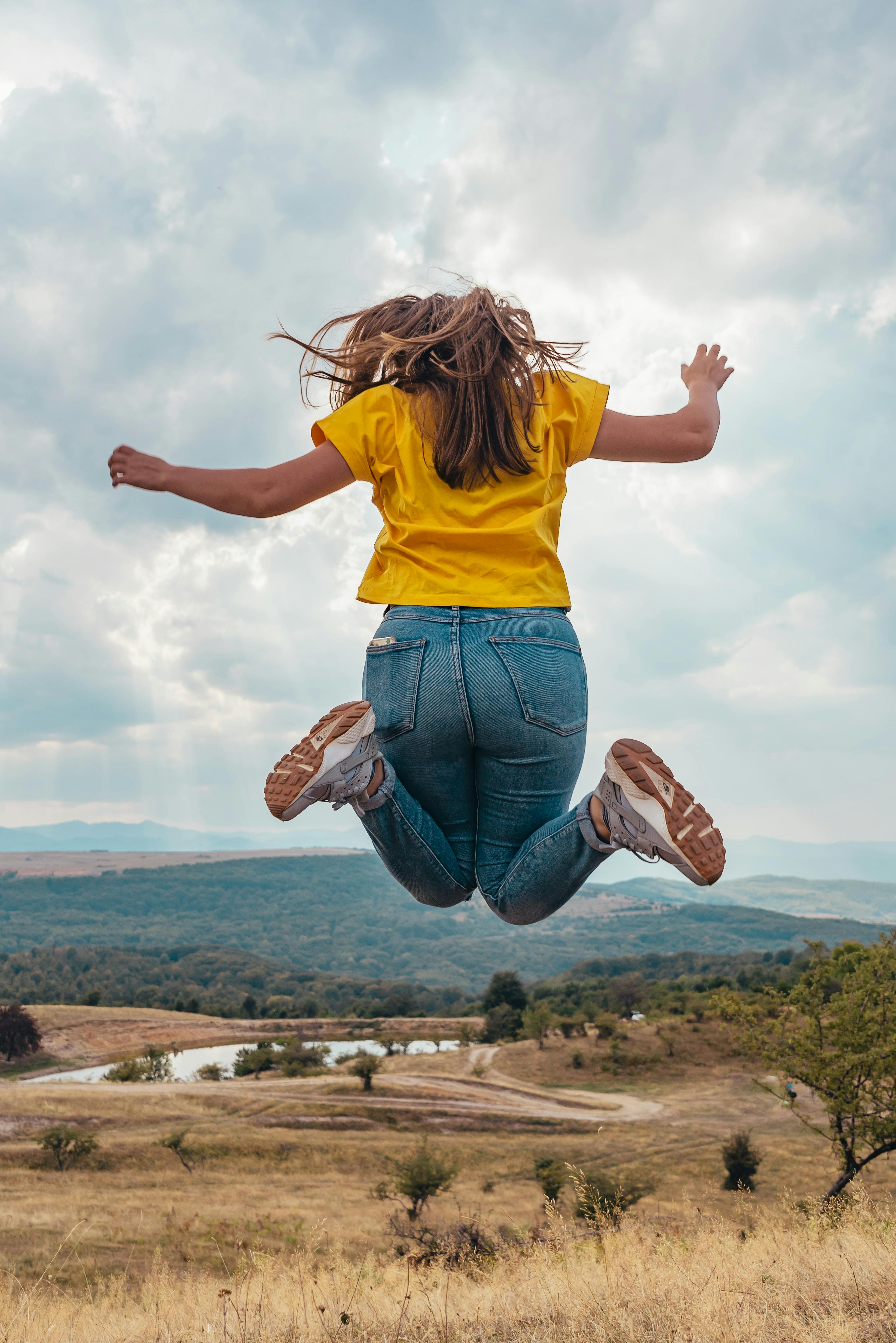 Back view Photo of Woman Wearing Yellow T-shirt and Jeans Jumping on ...