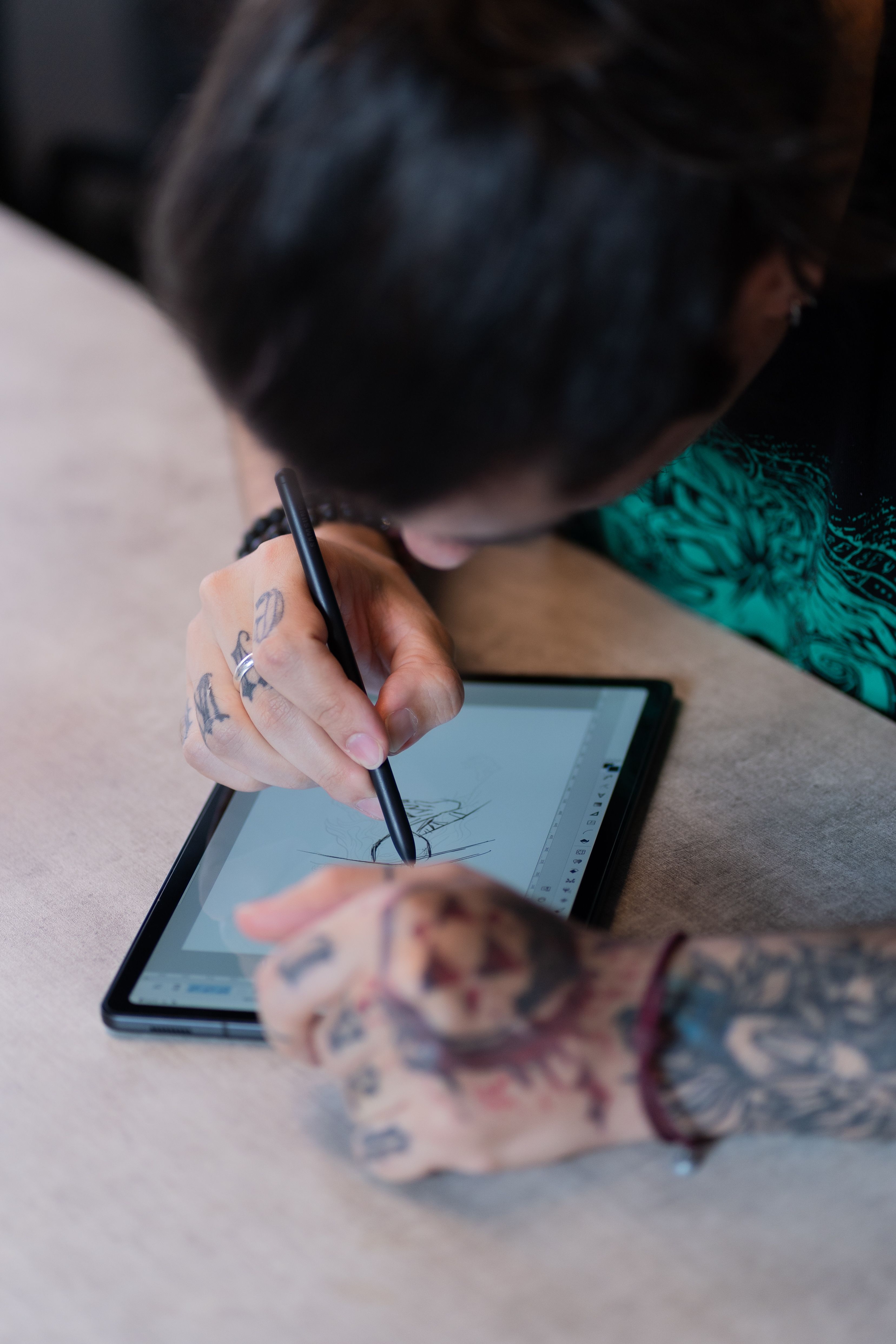 Smiling woman drawing on graphic tablet with pencil at table · Free ...
