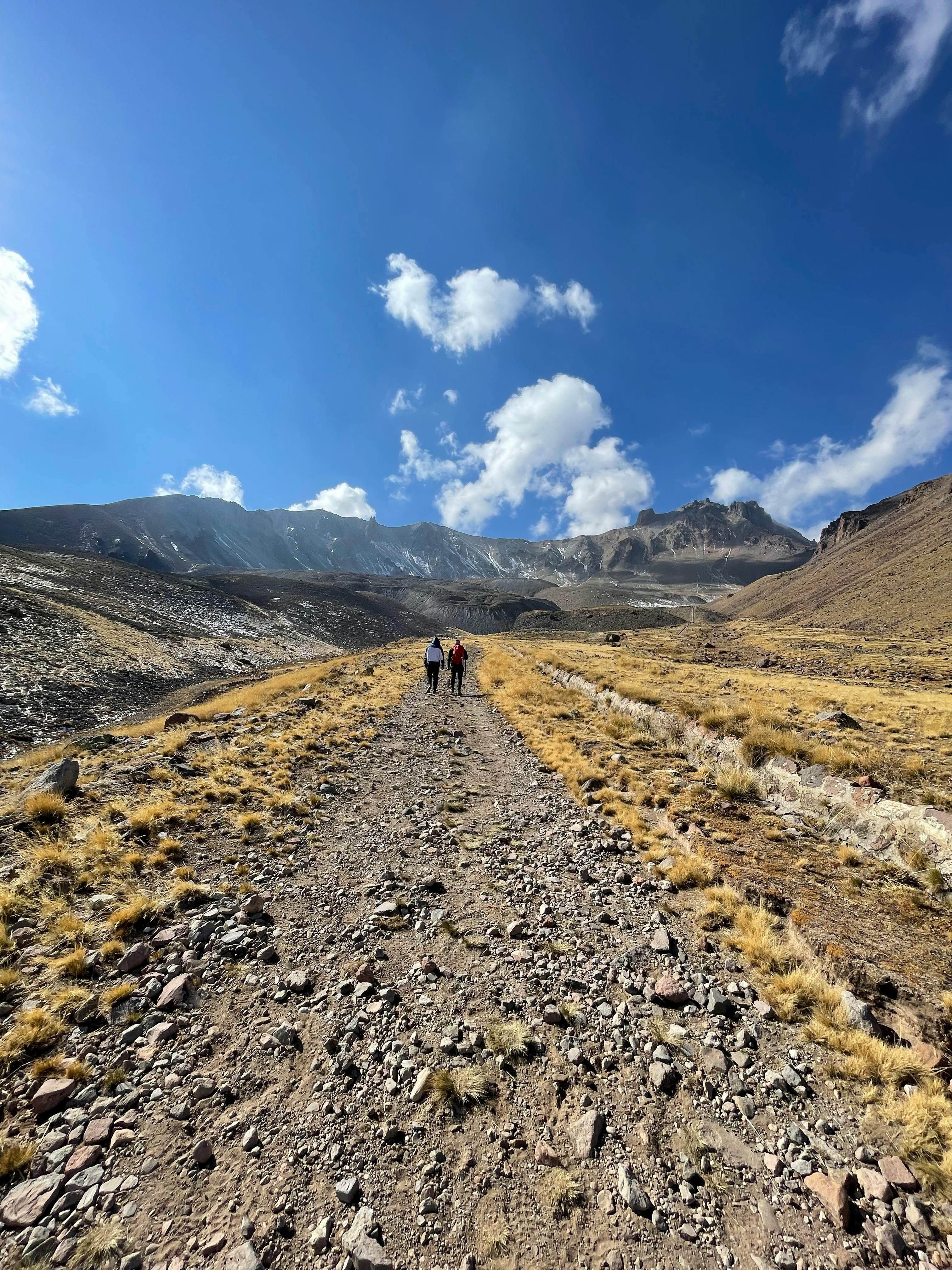 Trekking Through Rocky Mountain Path Under Blue Sky · Free Stock Photo