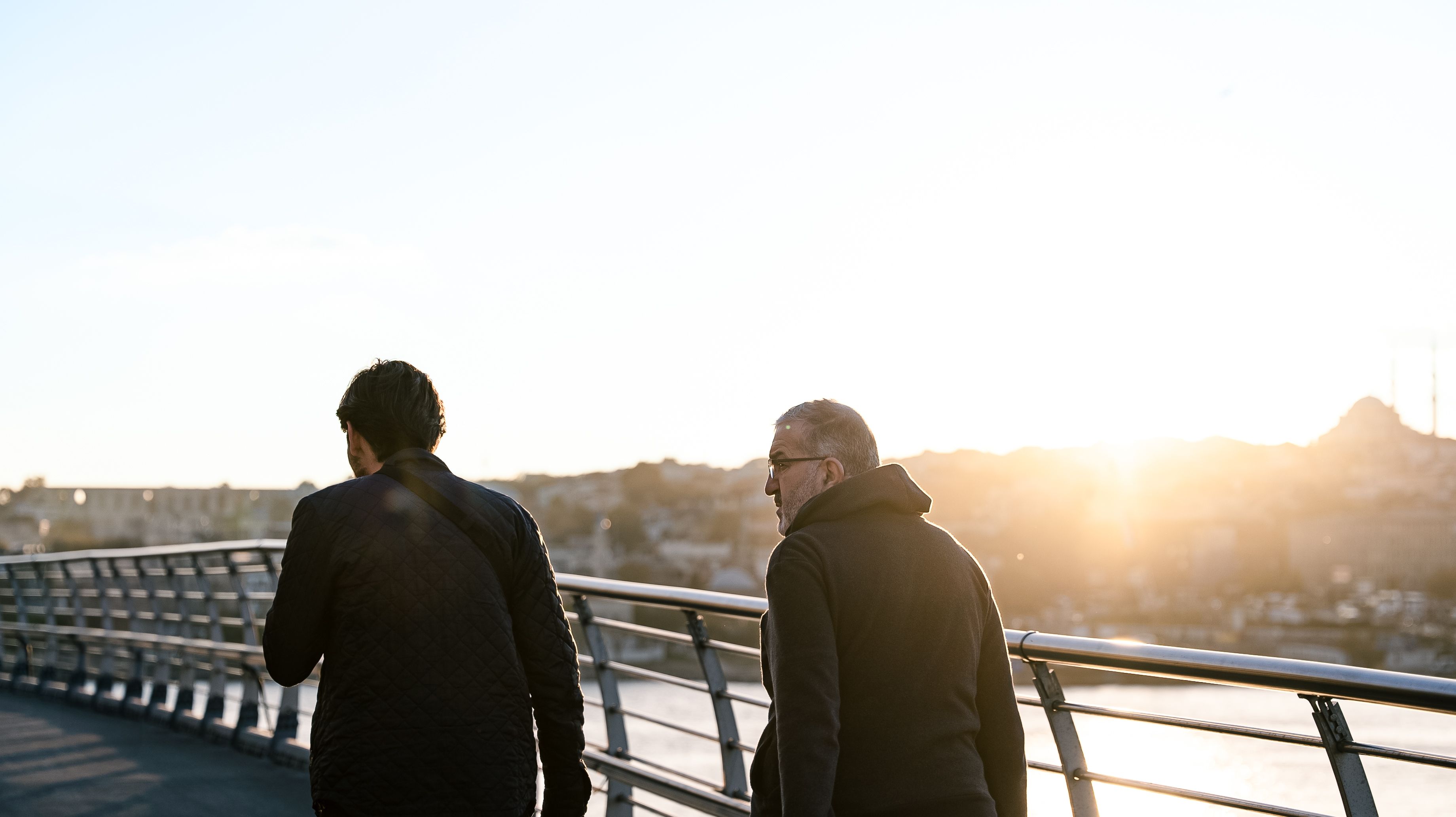 Two Men Walking on a Bridge at Sunset · Free Stock Photo