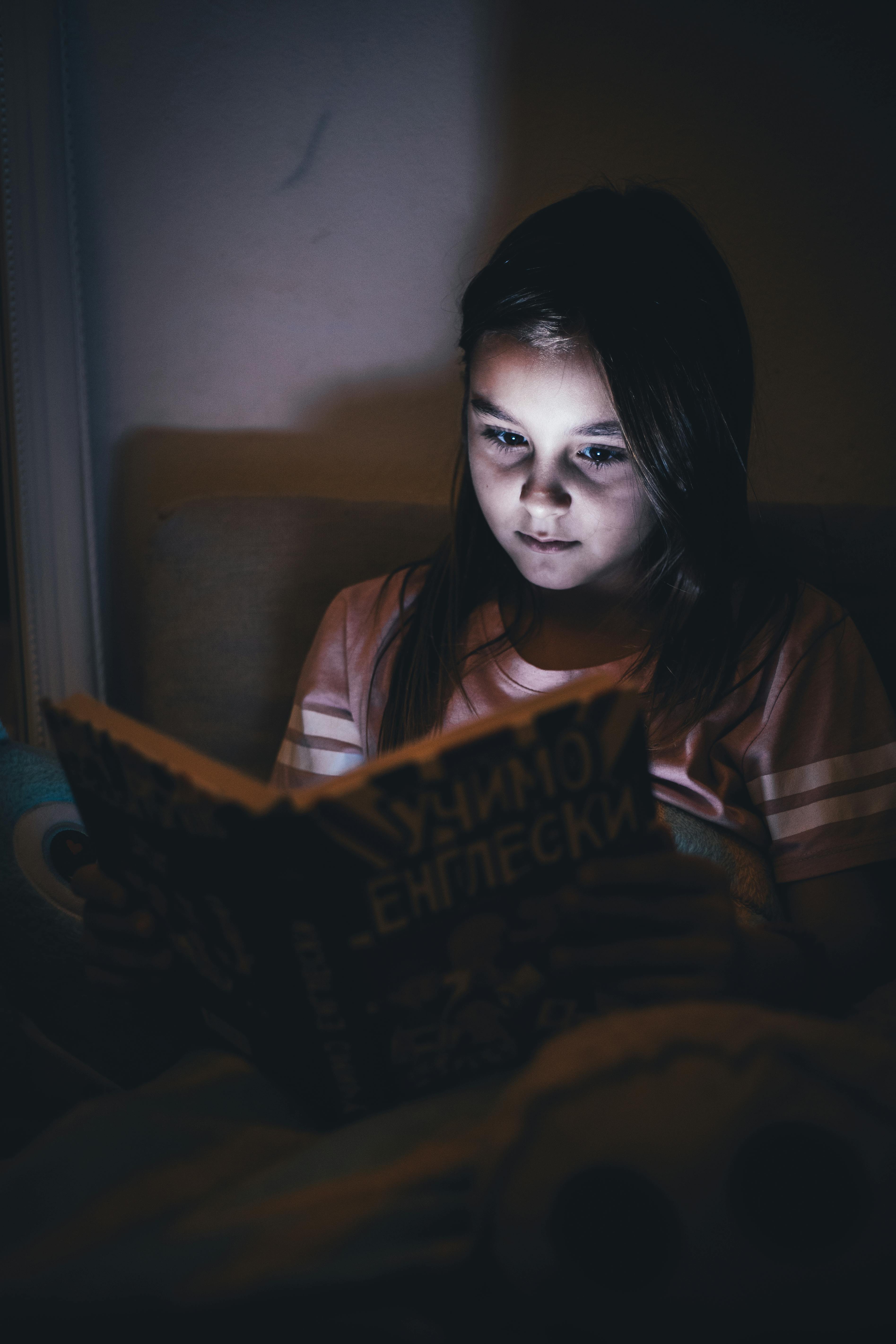 Young Girl Reading a Book at Night · Free Stock Photo