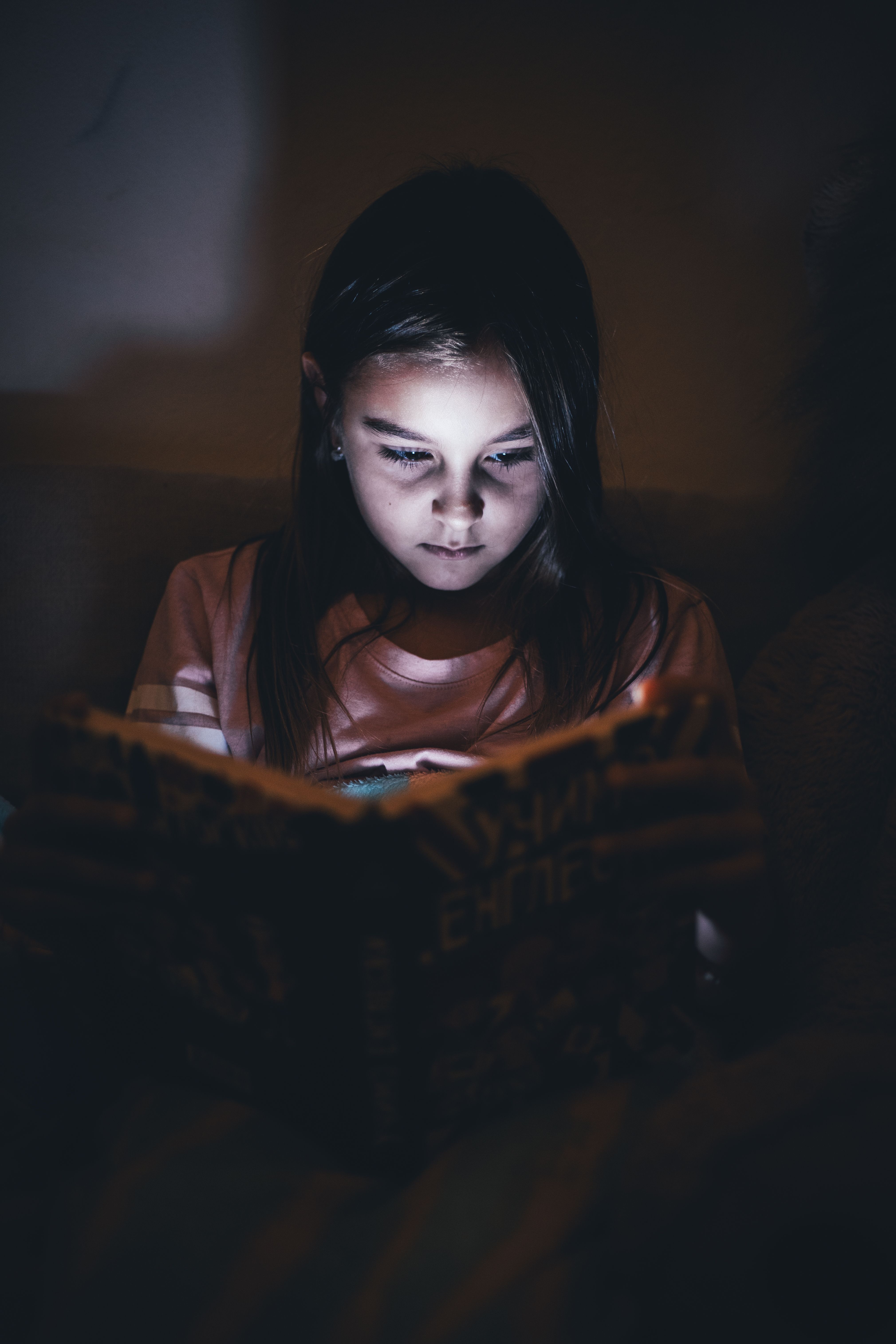 Young girl reading by flashlight in dark room · Free Stock Photo