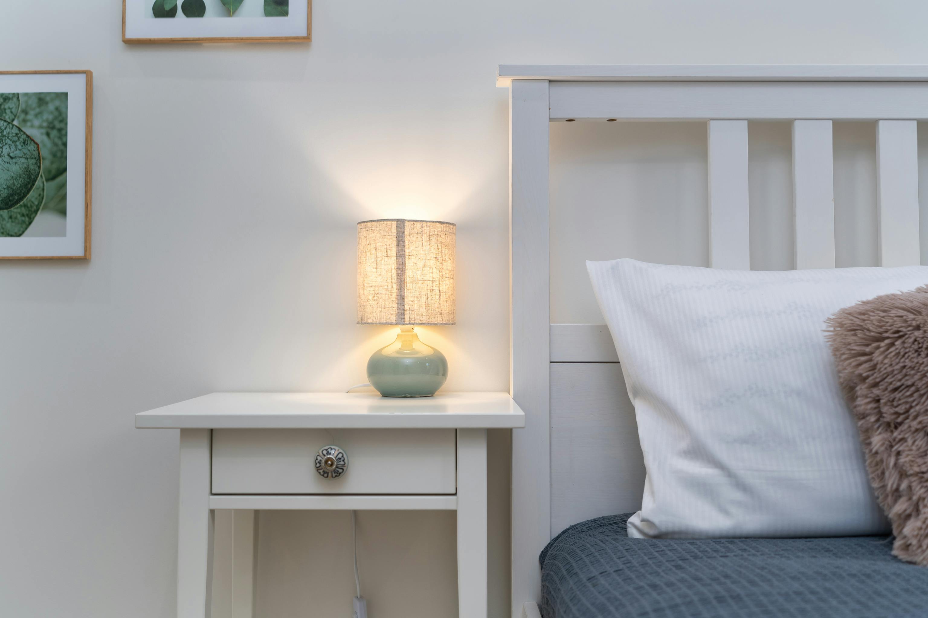 Cozy Bedroom Scene with Nightstand Lamp · Free Stock Photo