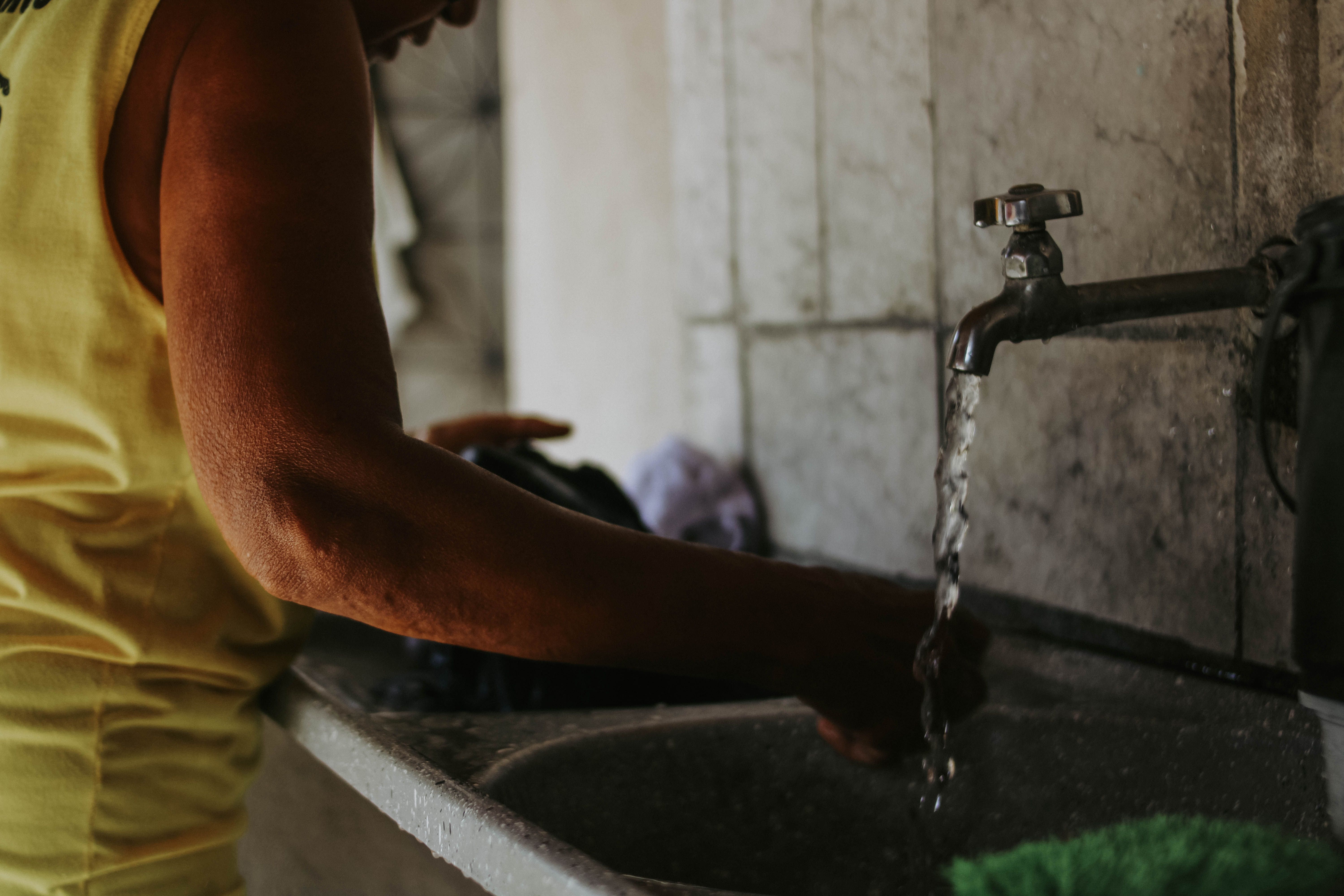 Person washing hands in rustic indoor sink · Free Stock Photo