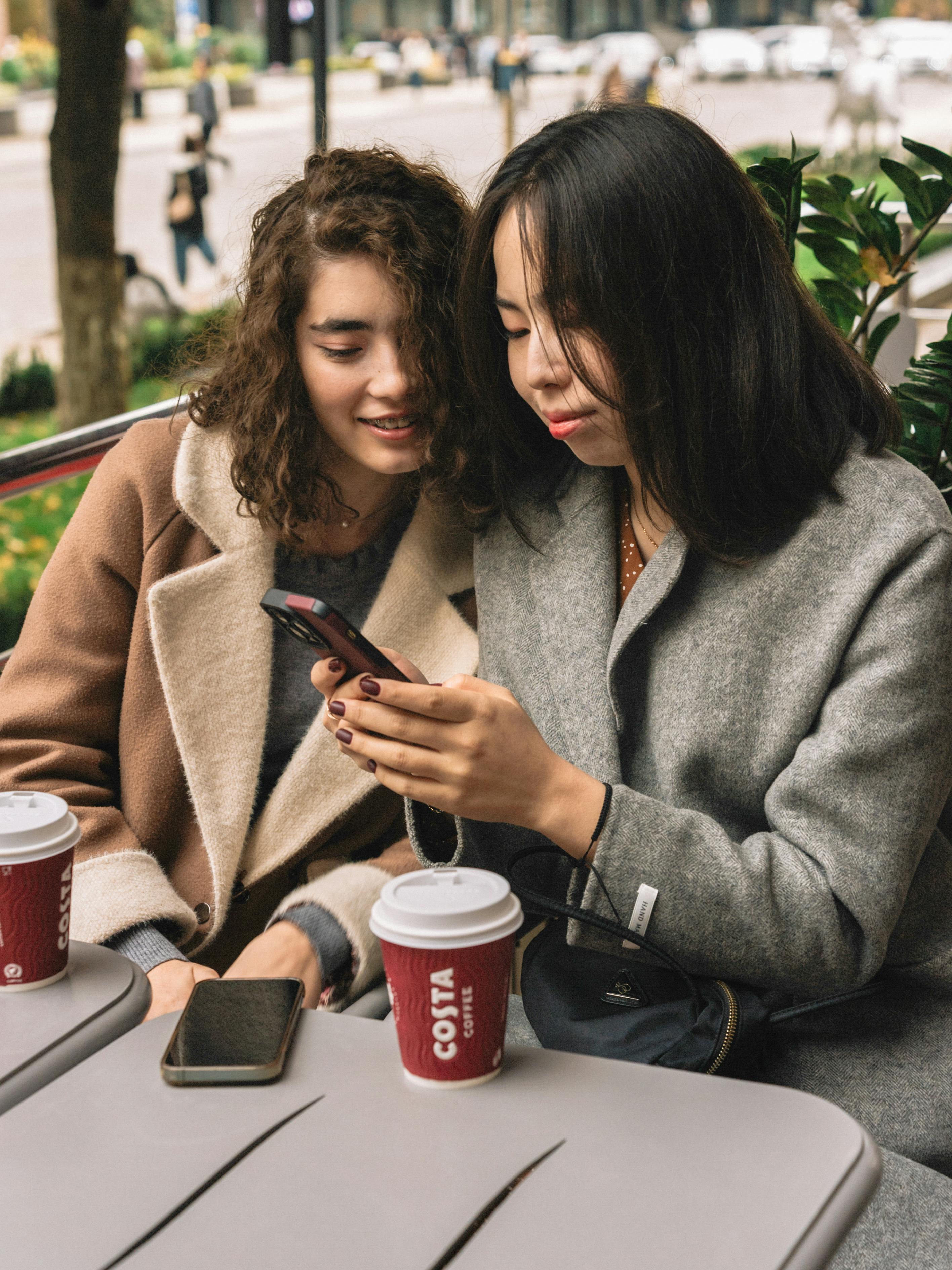 Friends sharing a coffee at an outdoor cafe · Free Stock Photo