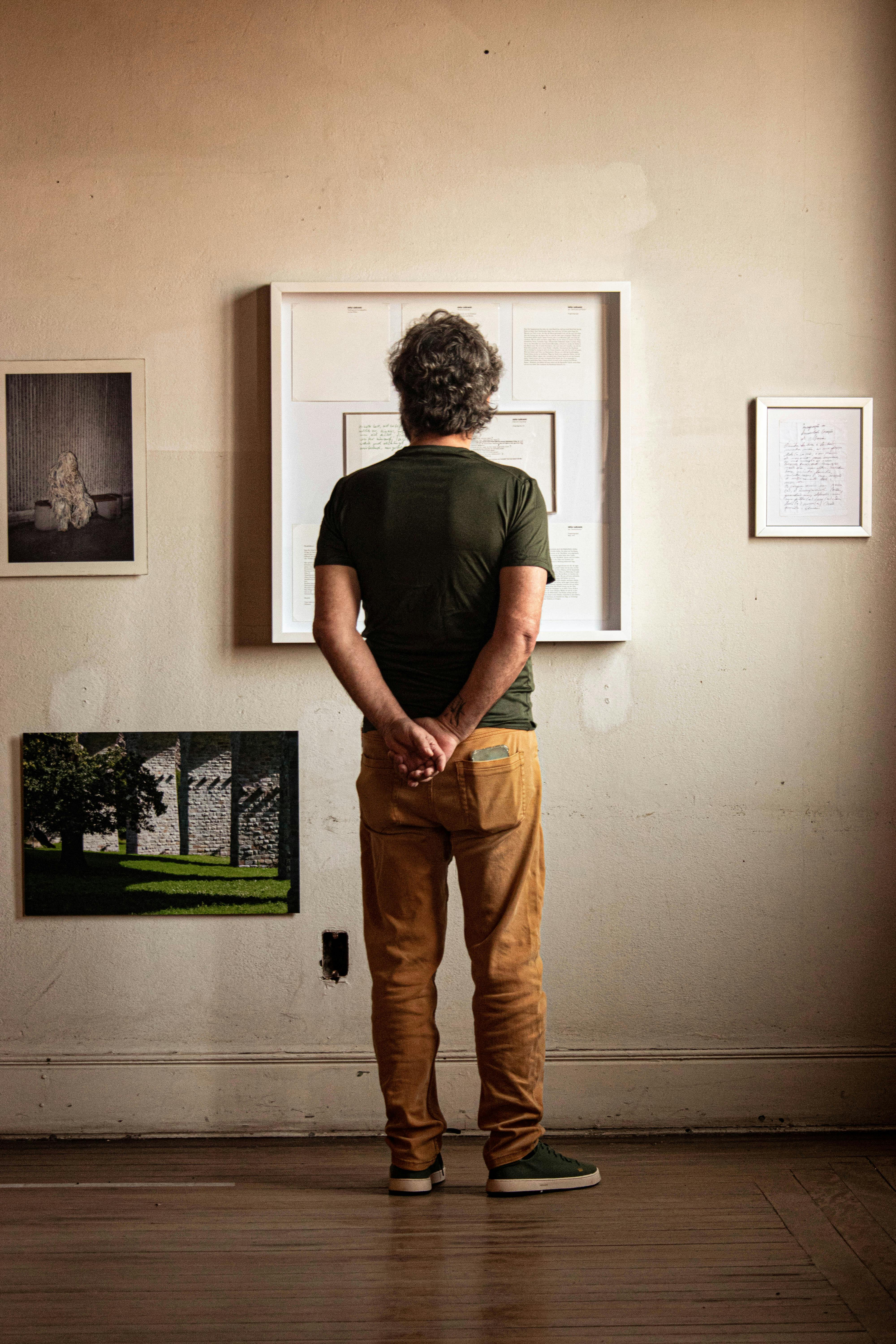 Man Observing Art in Gallery with Framed Pictures · Free Stock Photo