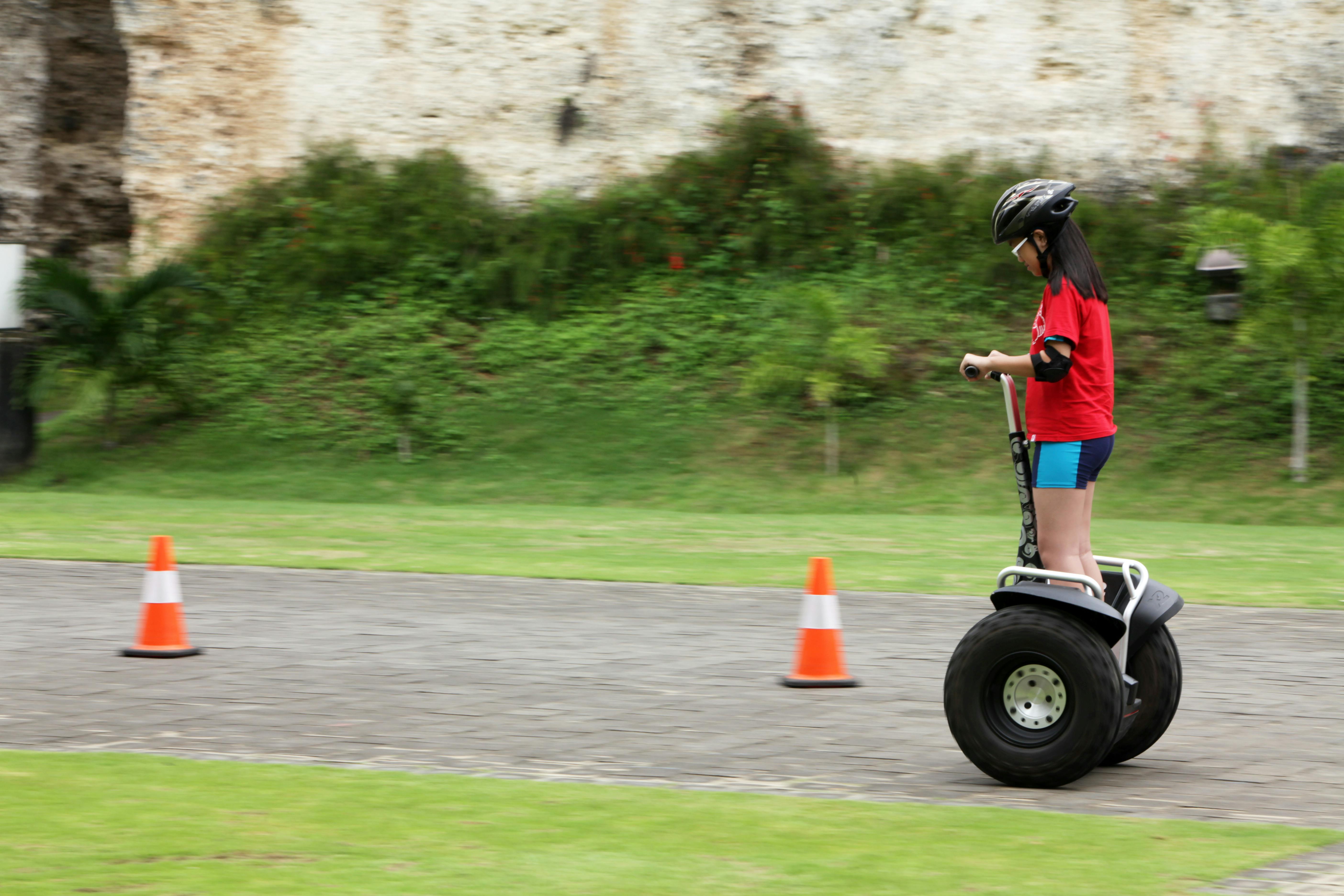 Young Girl Riding Segway Outdoors with Safety Gear · Free Stock Photo