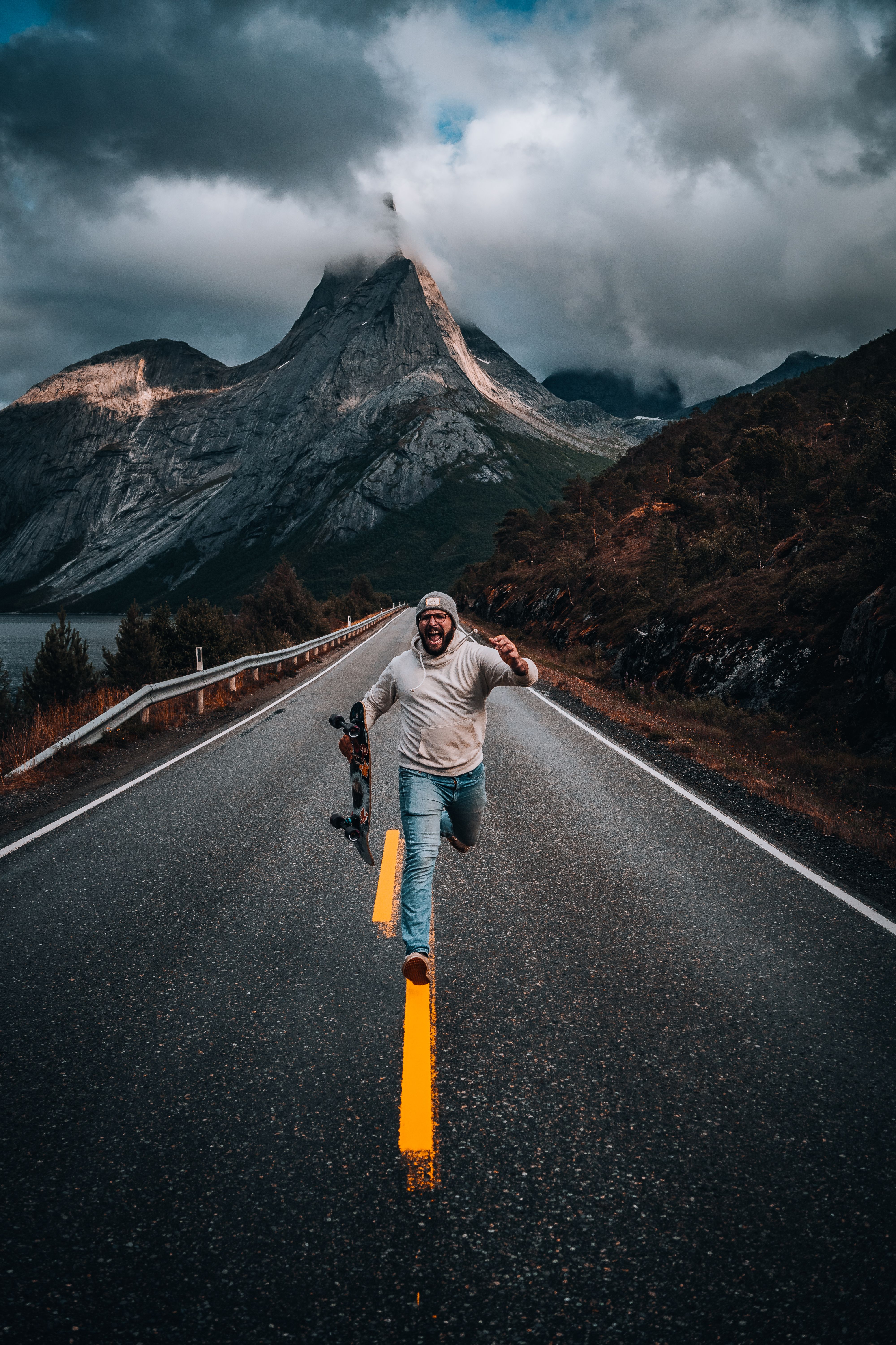 Man Running with Skateboard on Mountain Road · Free Stock Photo