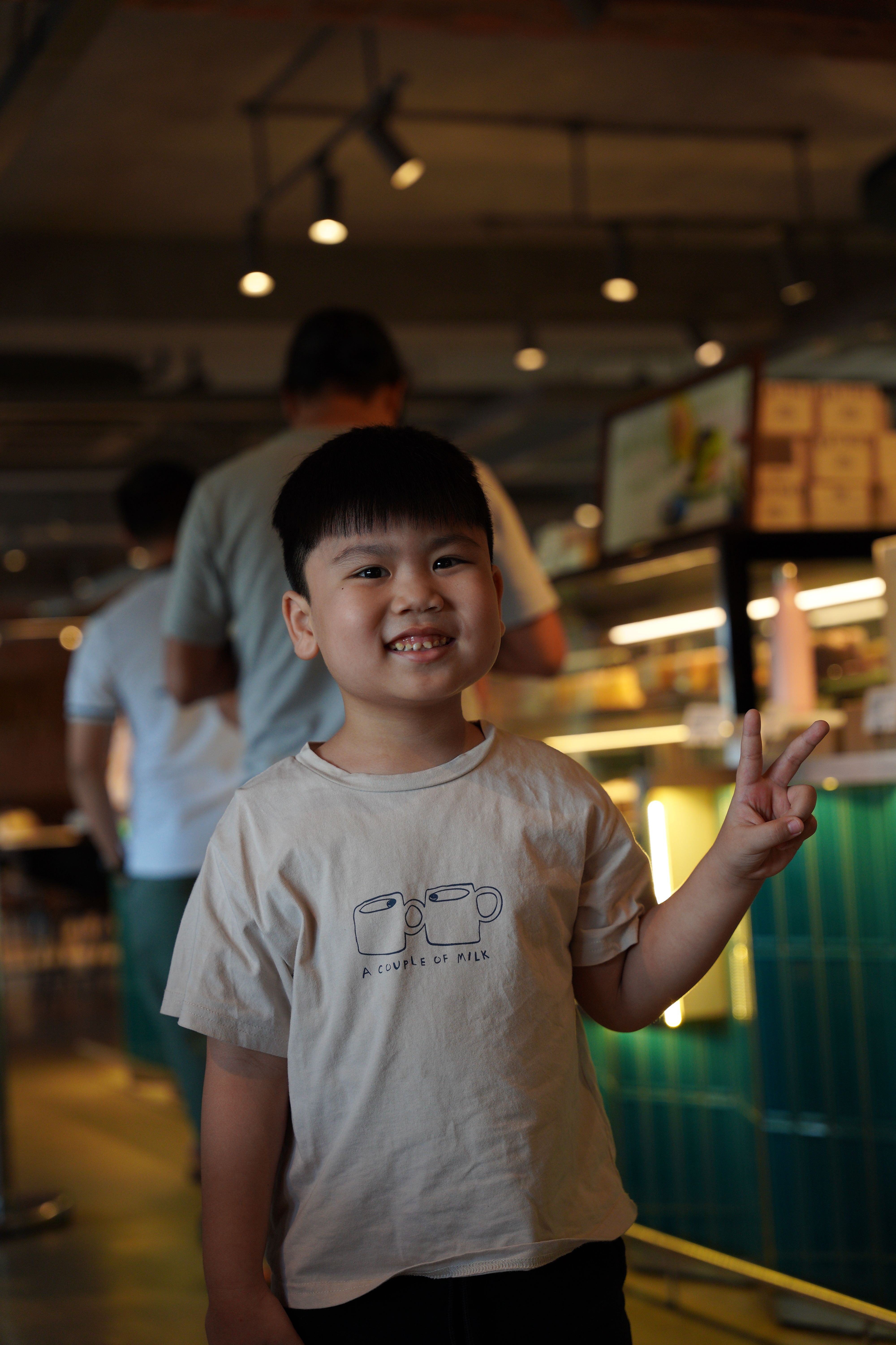 Smiling Child Making Peace Sign in Cafe · Free Stock Photo