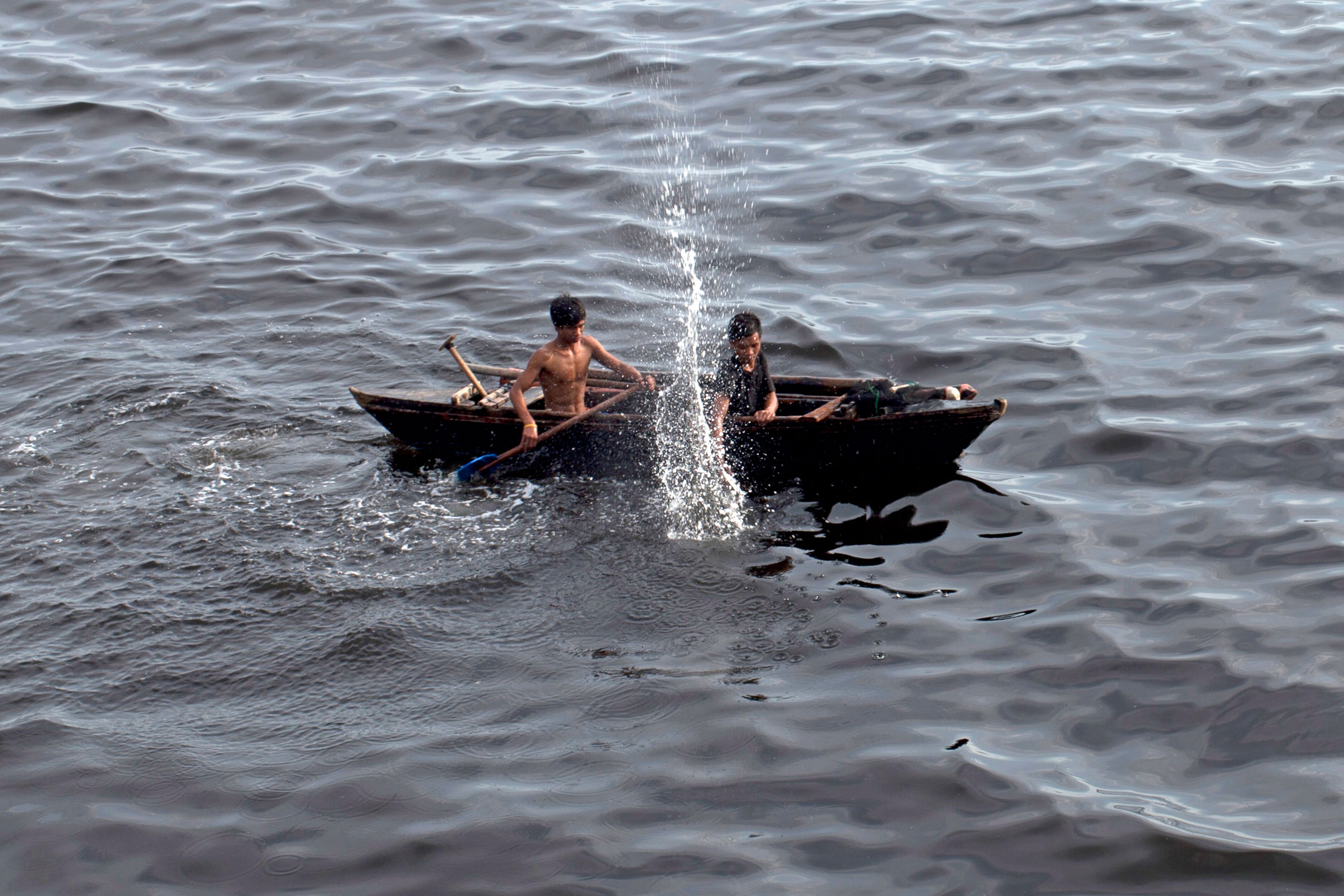 Boys Fishing in Small Wooden Boat on Open Water · Free Stock Photo