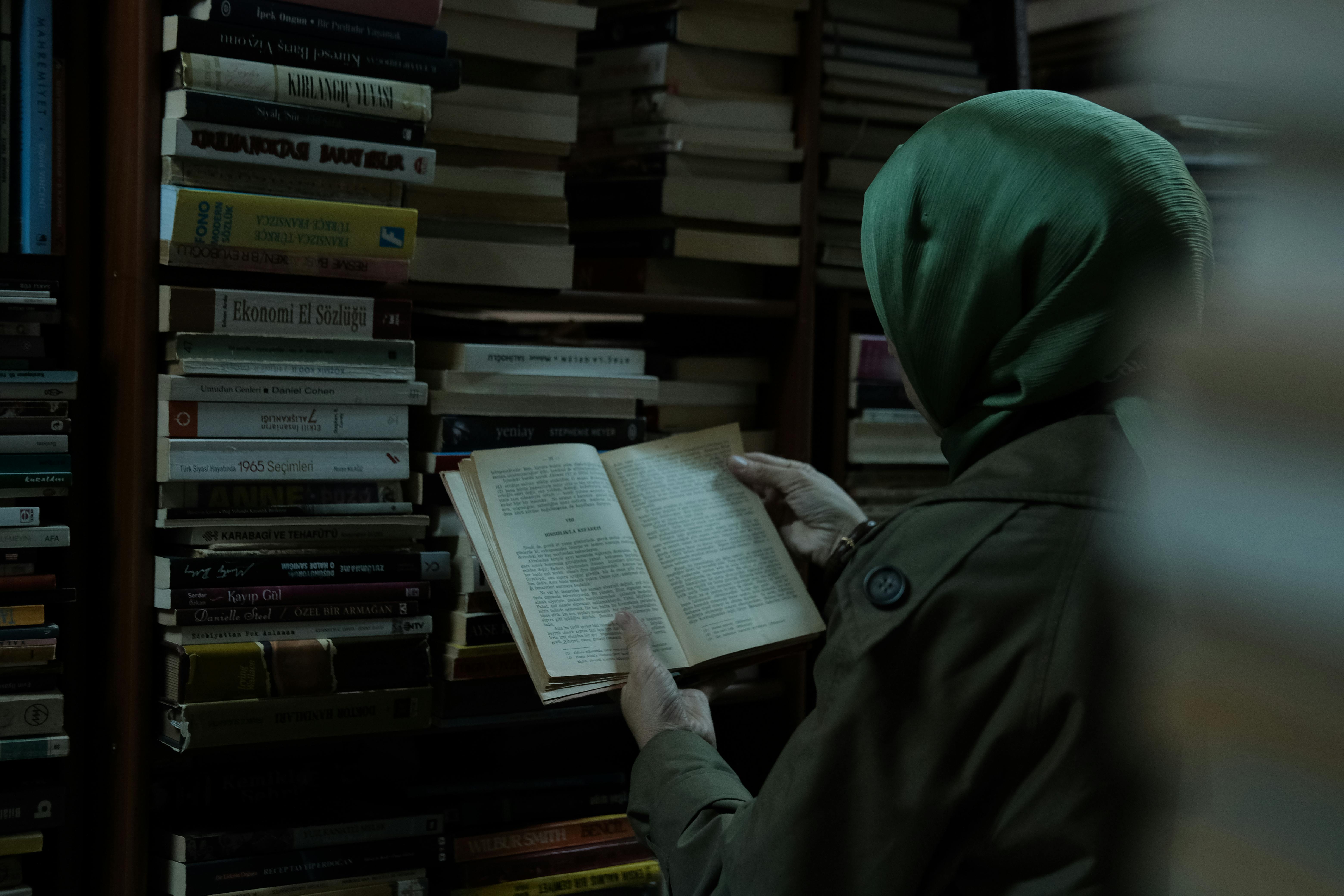 Person Reading in a Cozy Library with Bookshelves · Free Stock Photo
