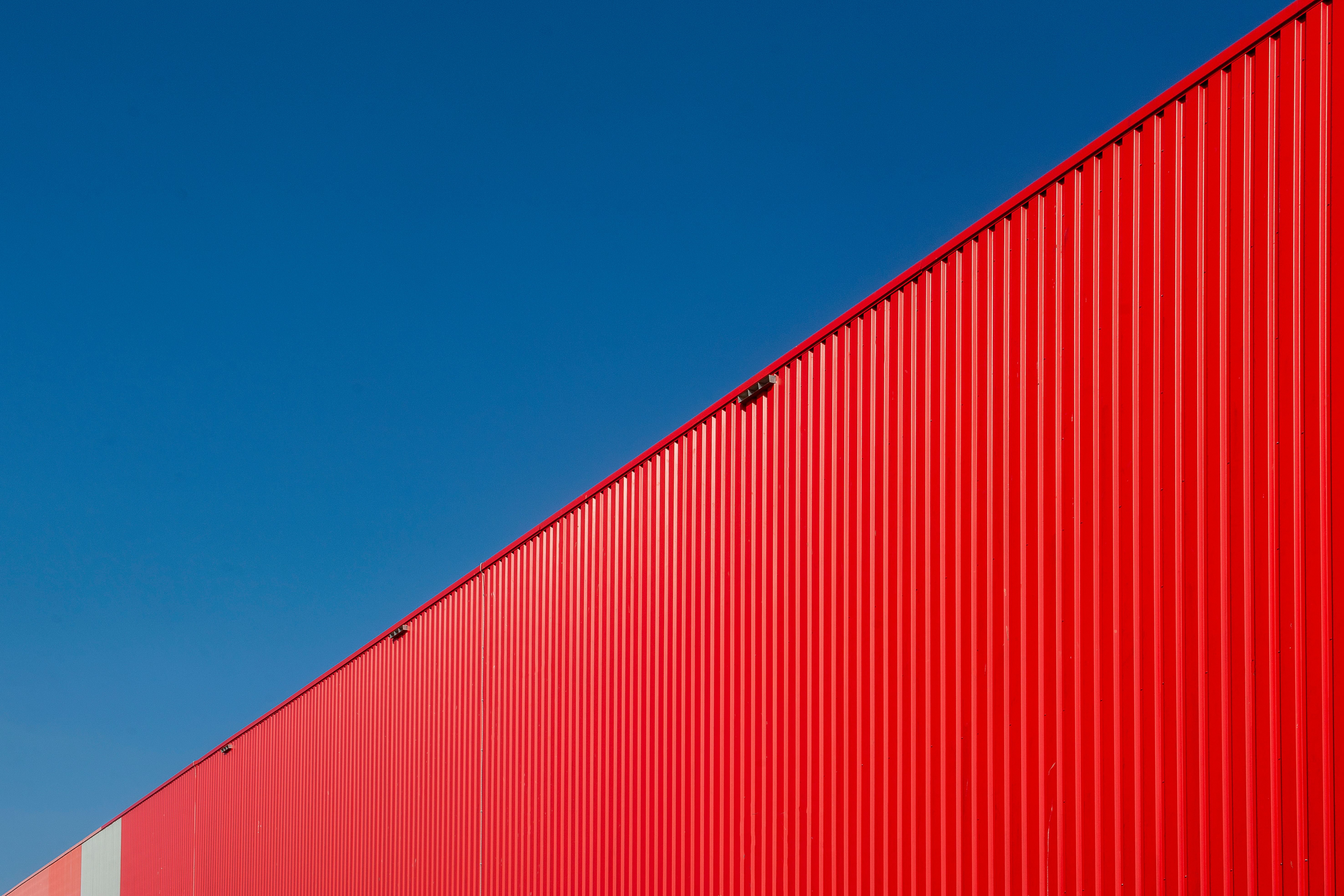Bold Red Industrial Wall Against Blue Sky · Free Stock Photo