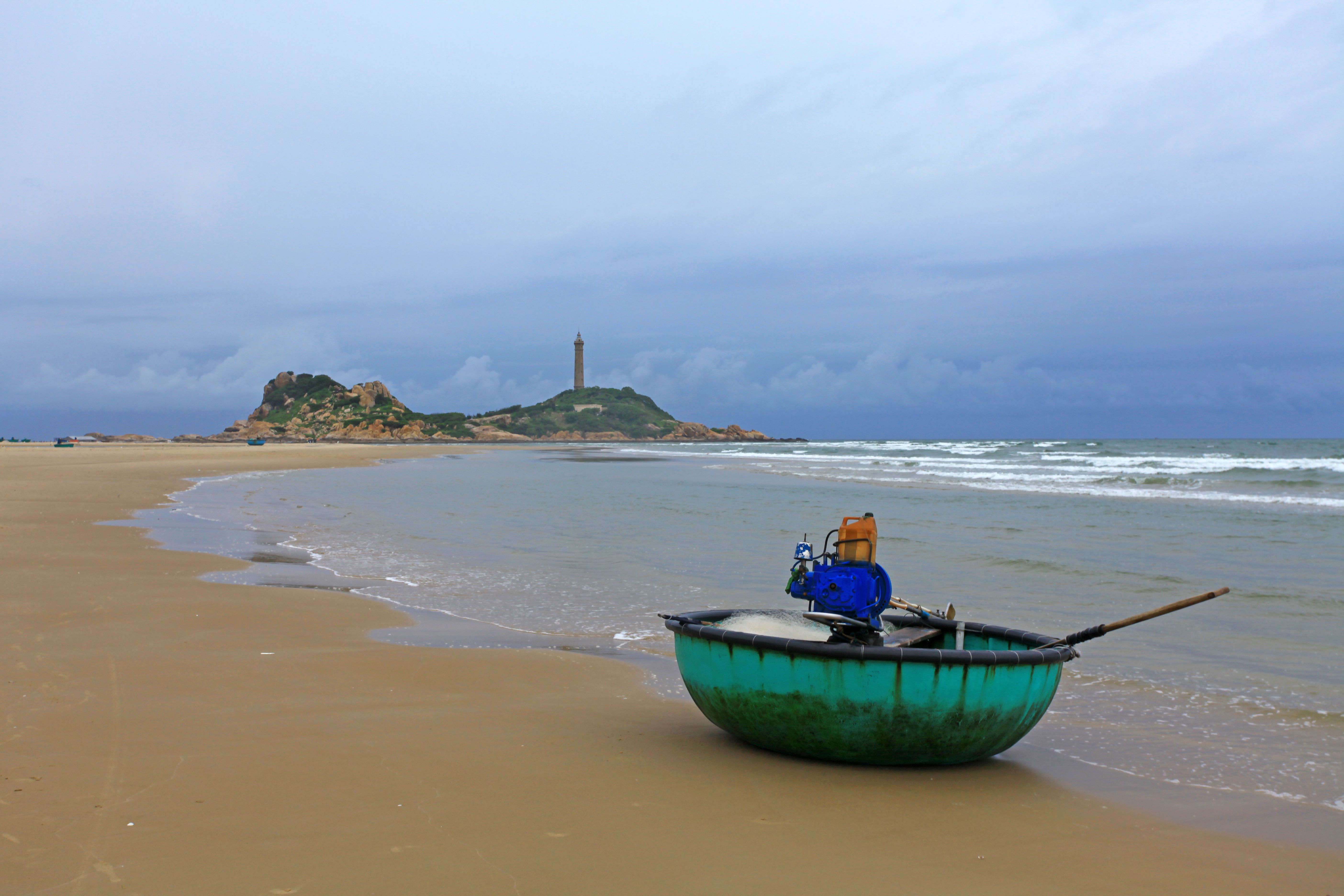 Round Boat on Sandy Beach by Lighthouse · Free Stock Photo