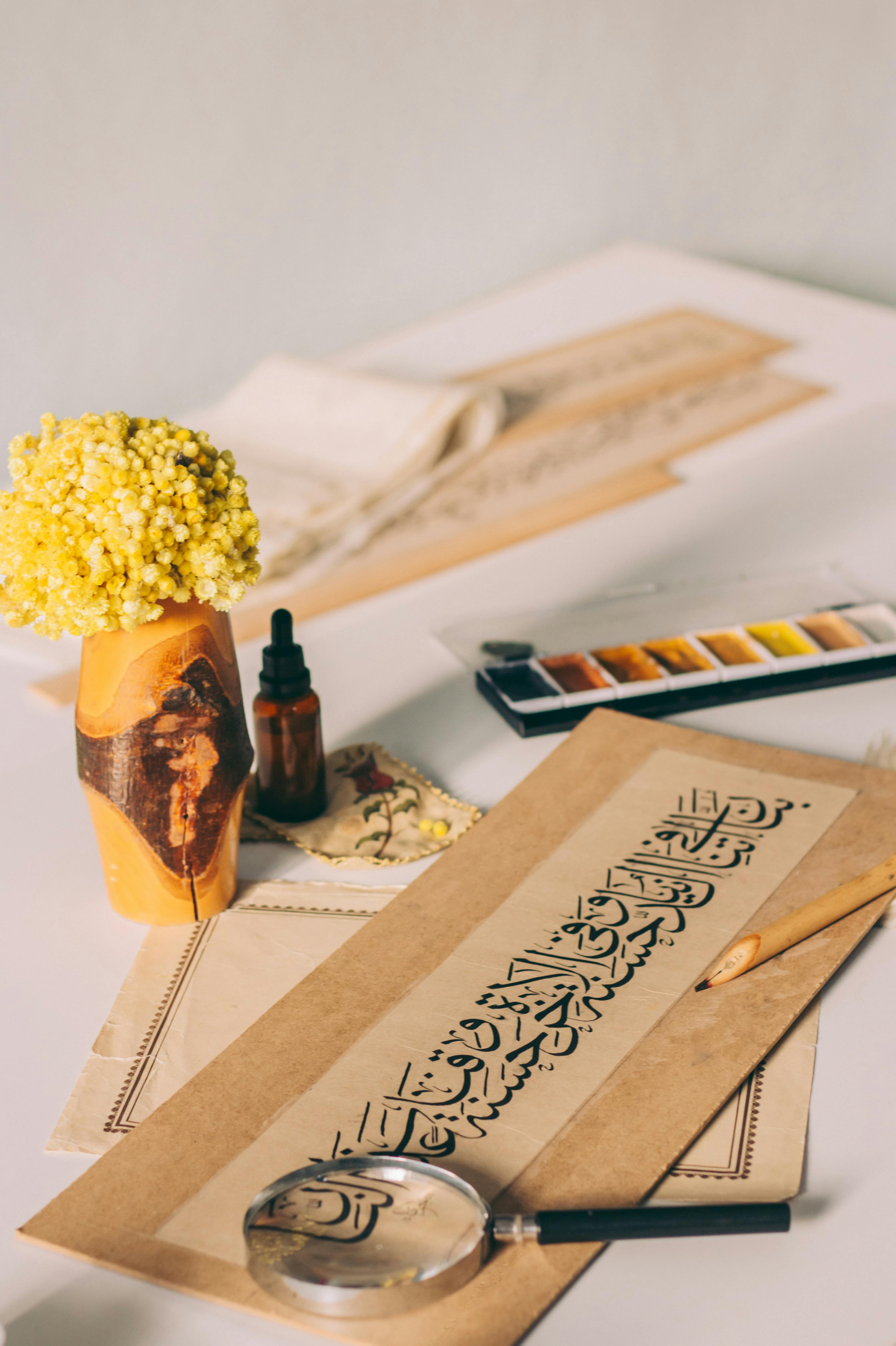 Elegant Arabic Calligraphy with Art Supplies on Table · Free Stock Photo