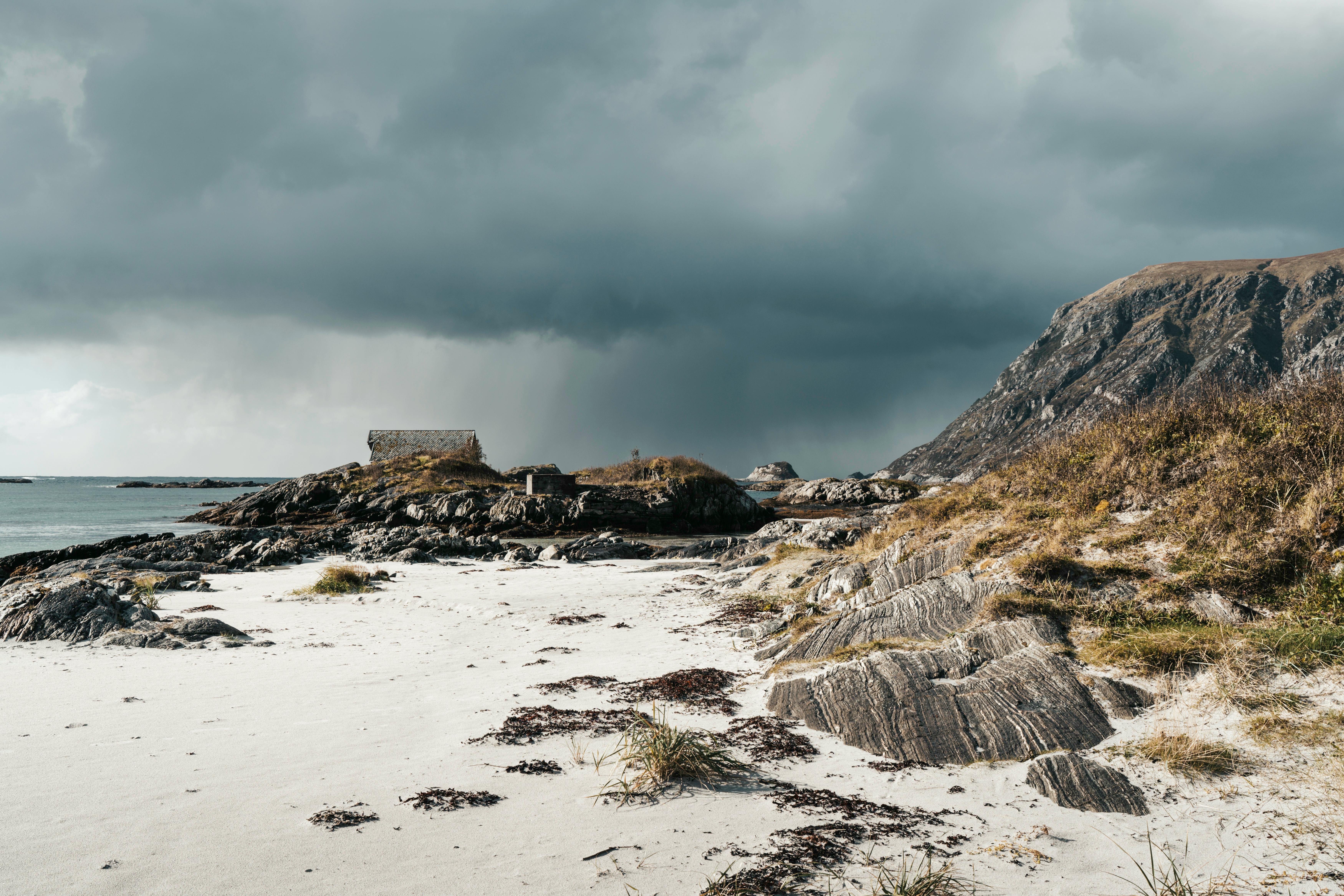 Scenic Beach with Dramatic Clouds and Cliffs · Free Stock Photo