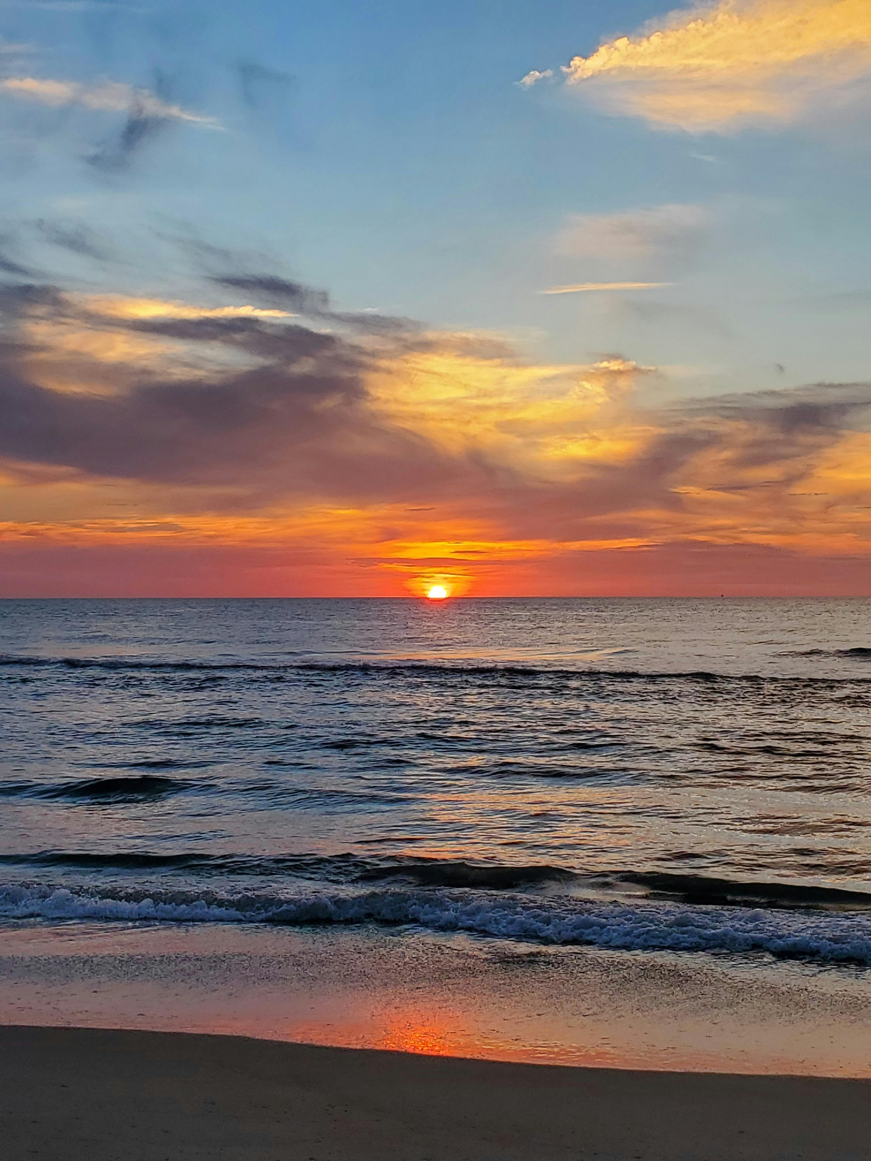 Dramatic Beach Sunset Over Calm Ocean Waters · Free Stock Photo
