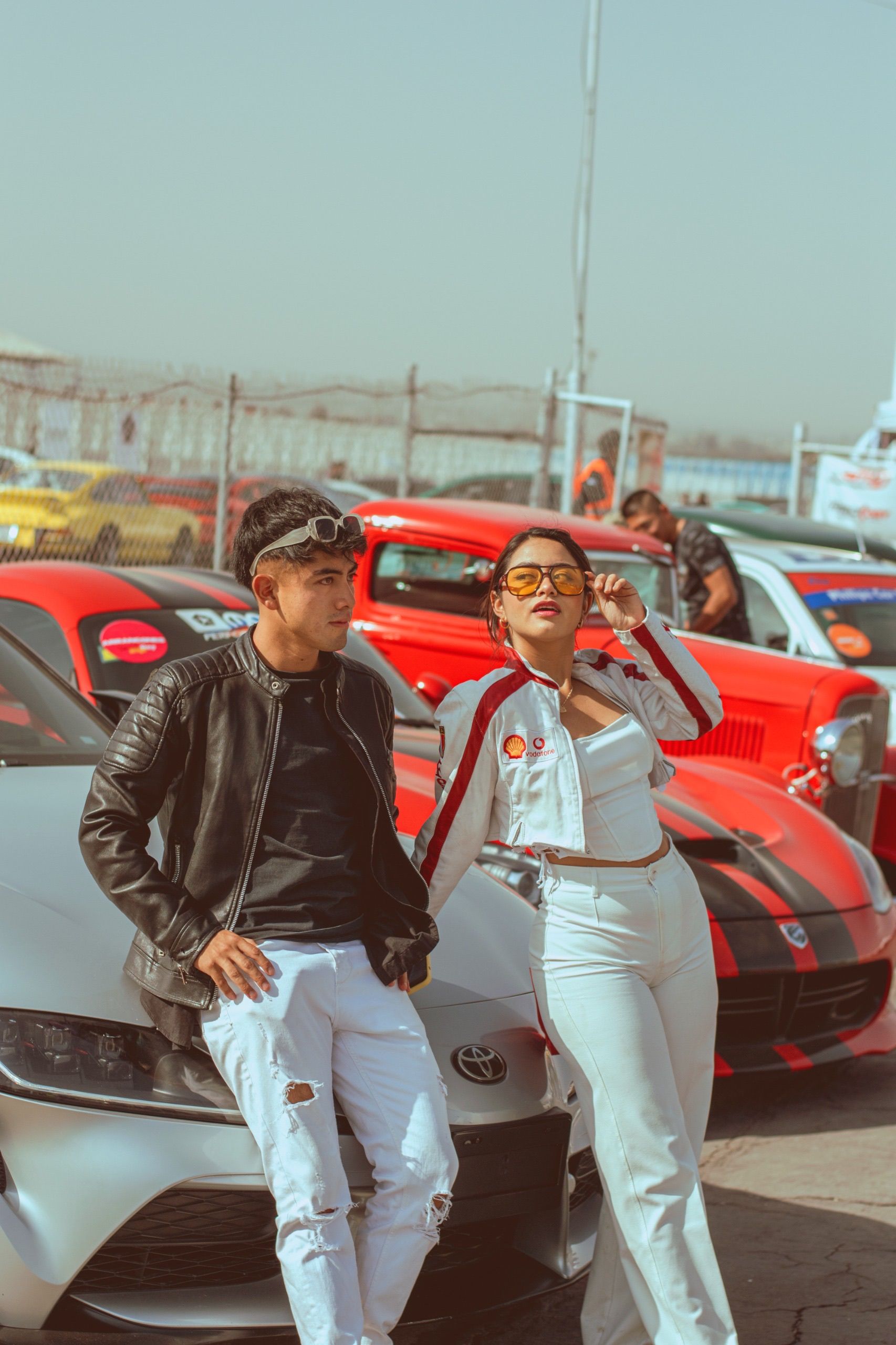 Couple Posing with Sports Cars at Outdoor Car Show · Free Stock Photo