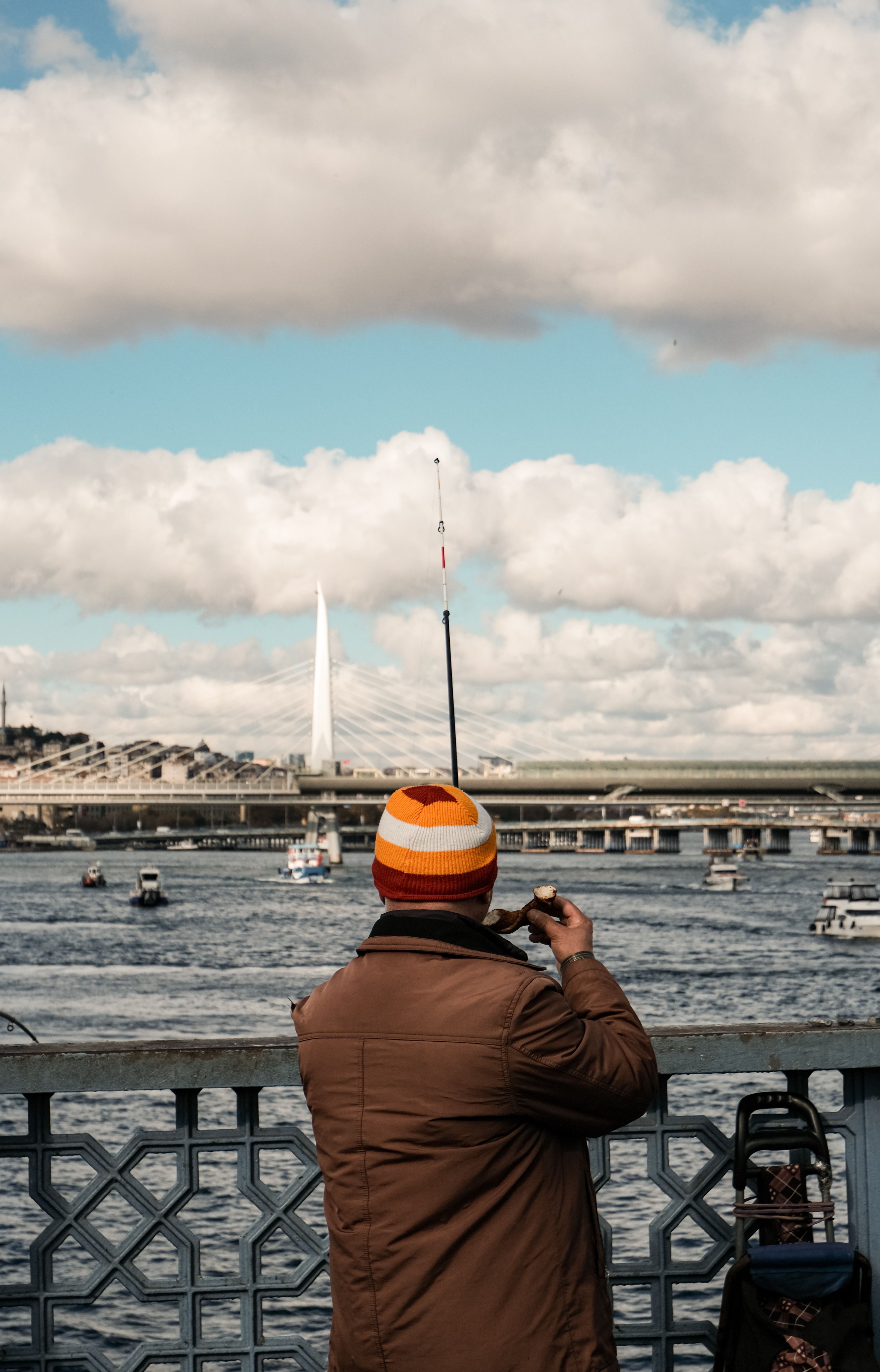 Fisherman on Bridge Over Scenic Waterway · Free Stock Photo