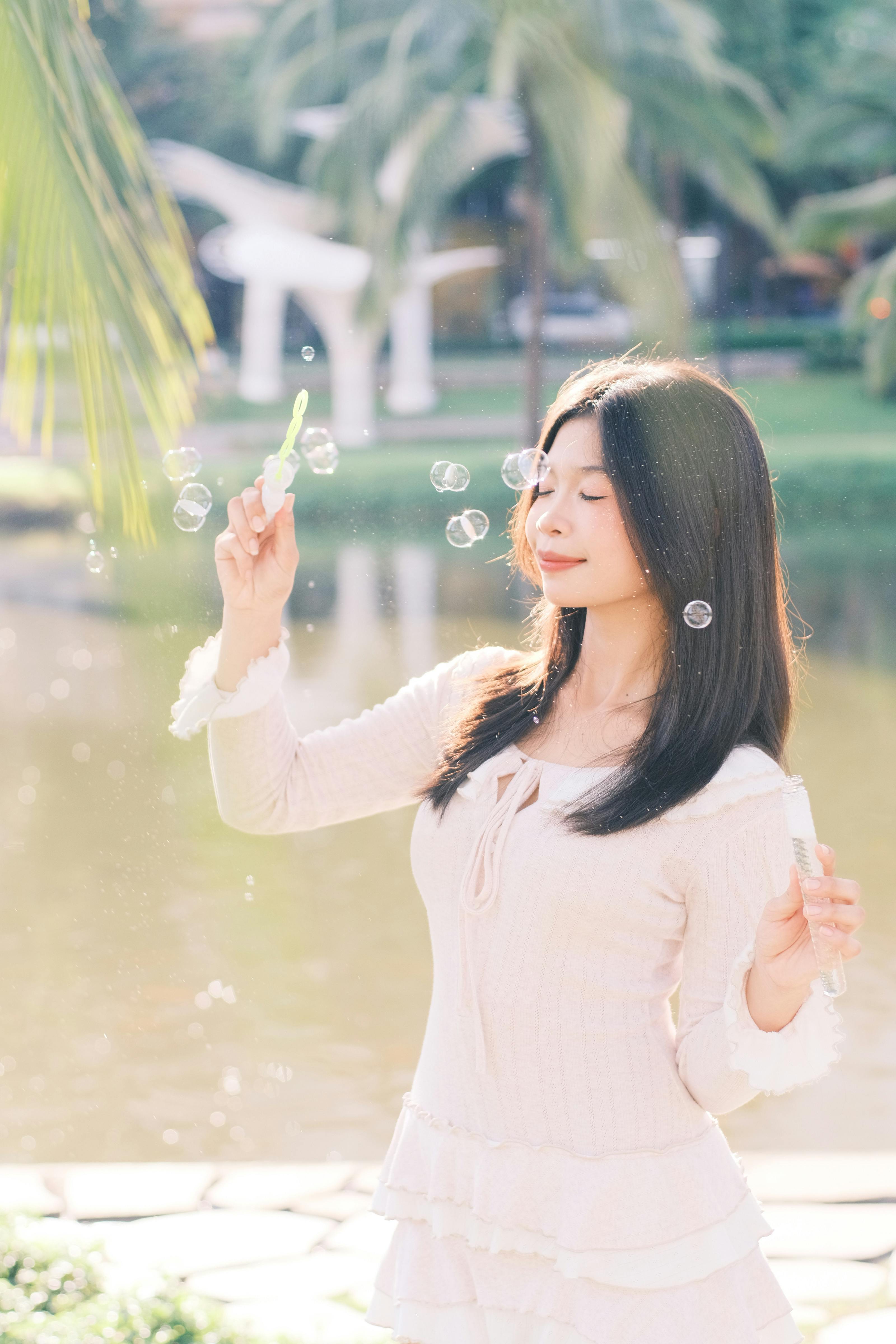 Young Woman Blowing Bubbles Near Pond Outdoors · Free Stock Photo