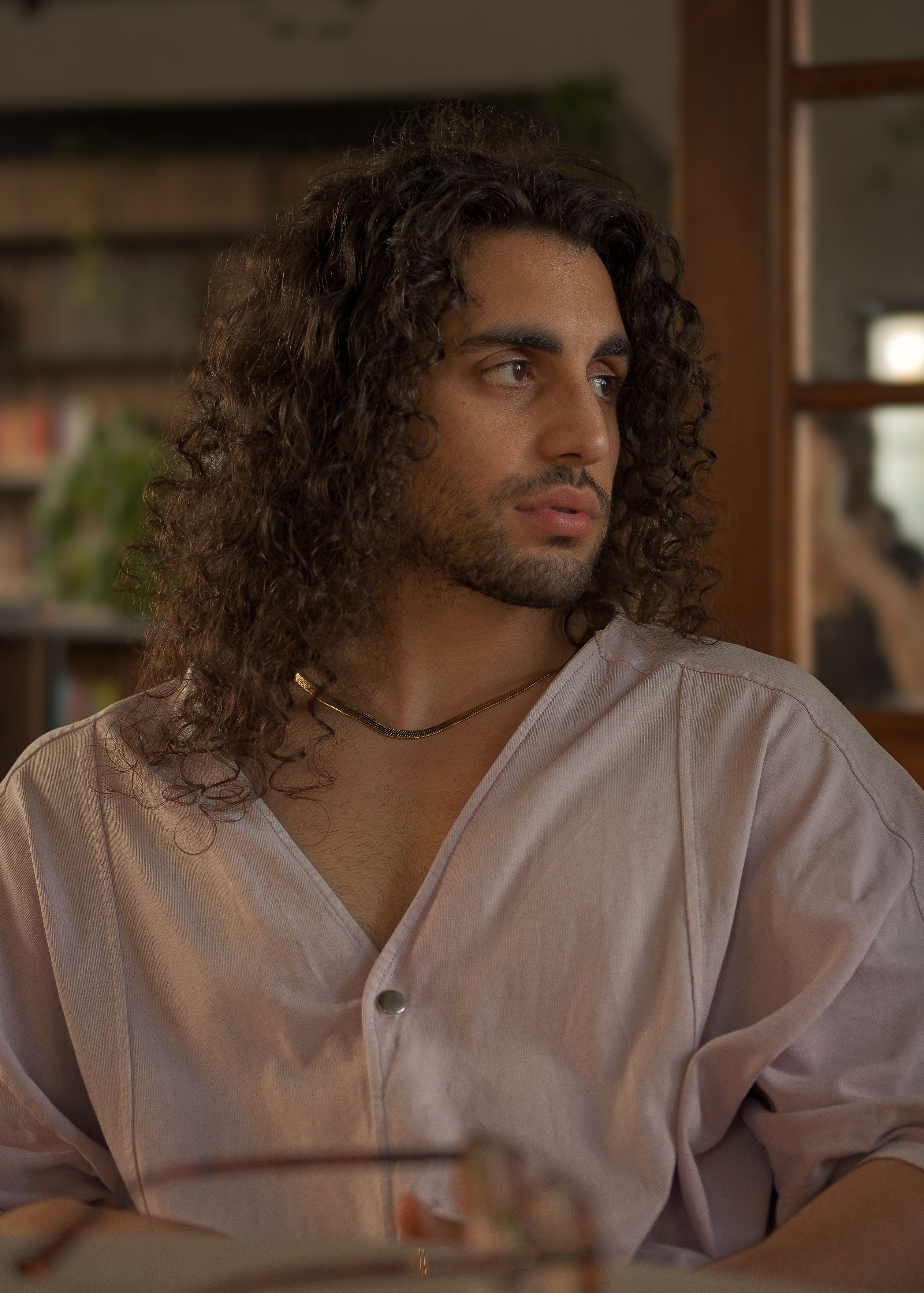 Reflective Adult with Curly Hair in Relaxed Setting · Free Stock Photo