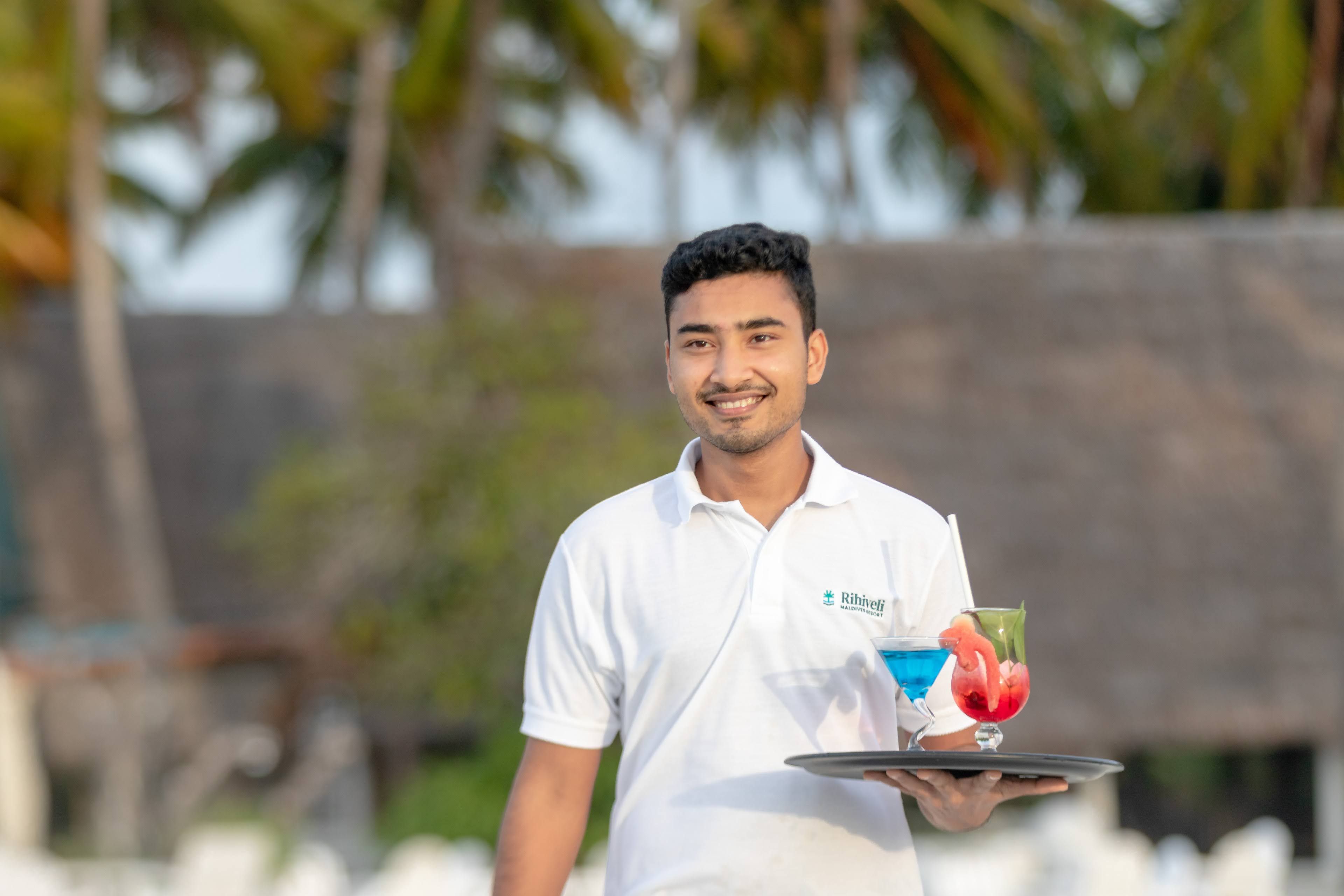 Smiling Waiter Serving Cocktails at Tropical Resort · Free Stock Photo