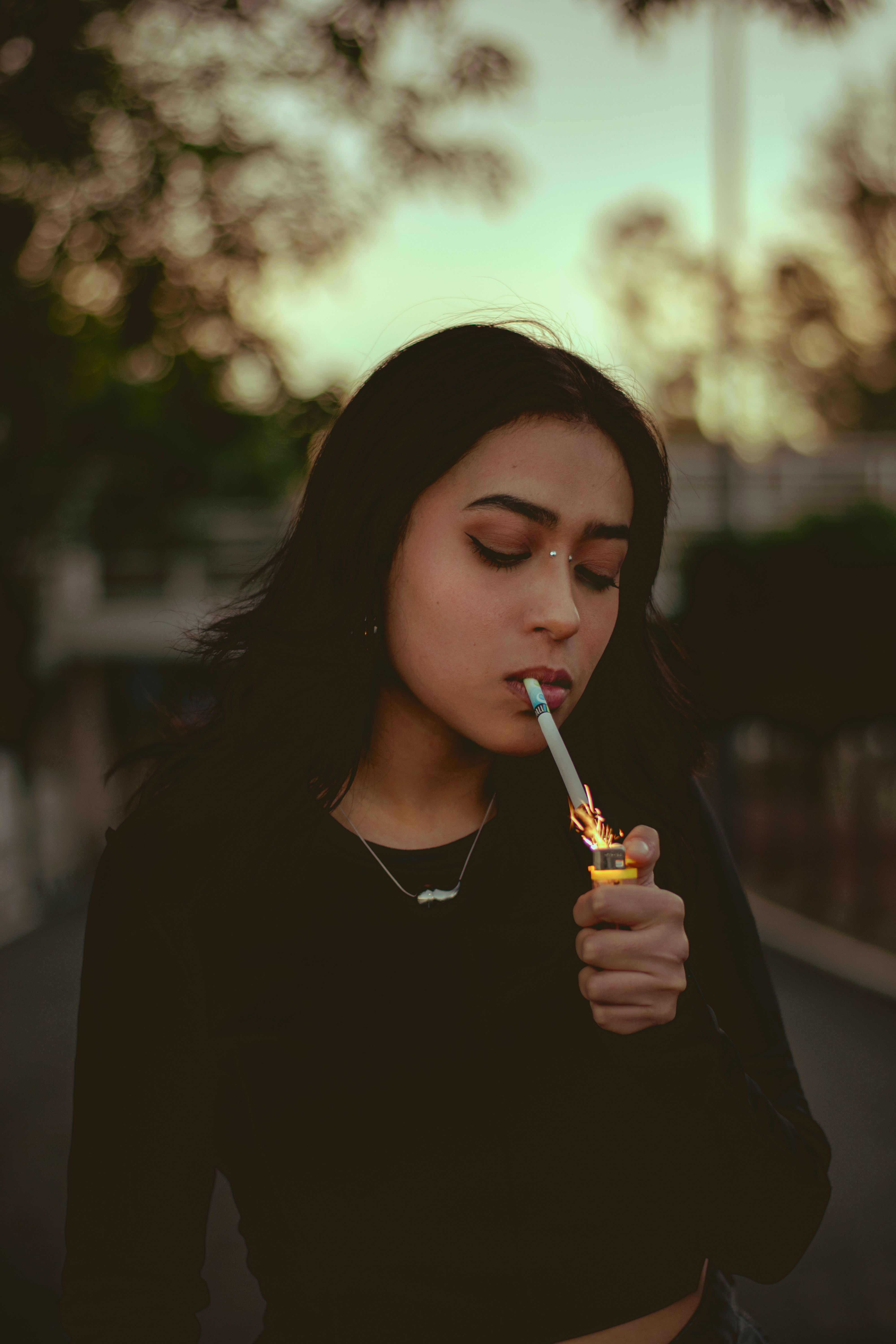 Young Woman Lighting Cigarette at Twilight · Free Stock Photo