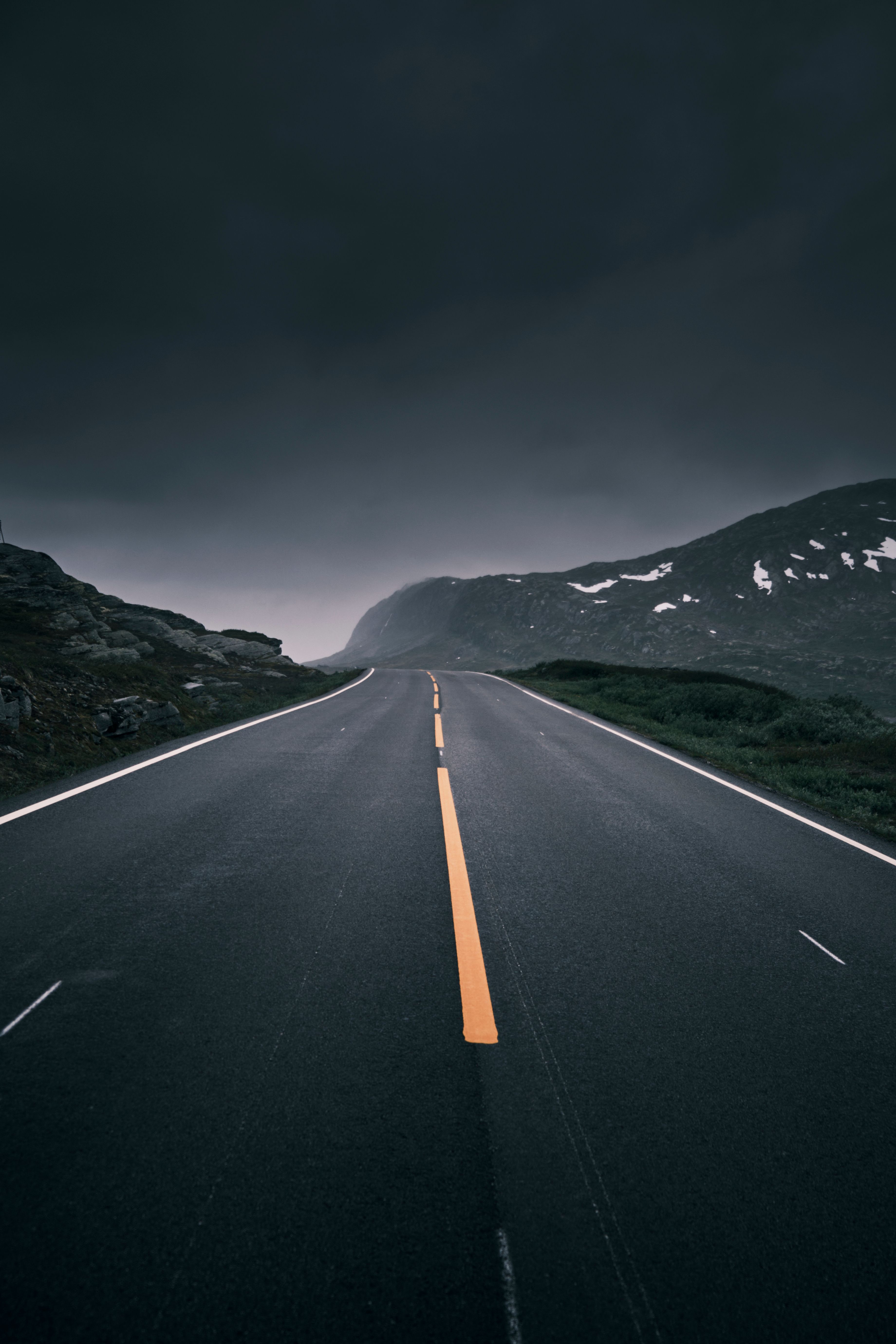 Dramatic Mountain Road Under Dark Skies · Free Stock Photo