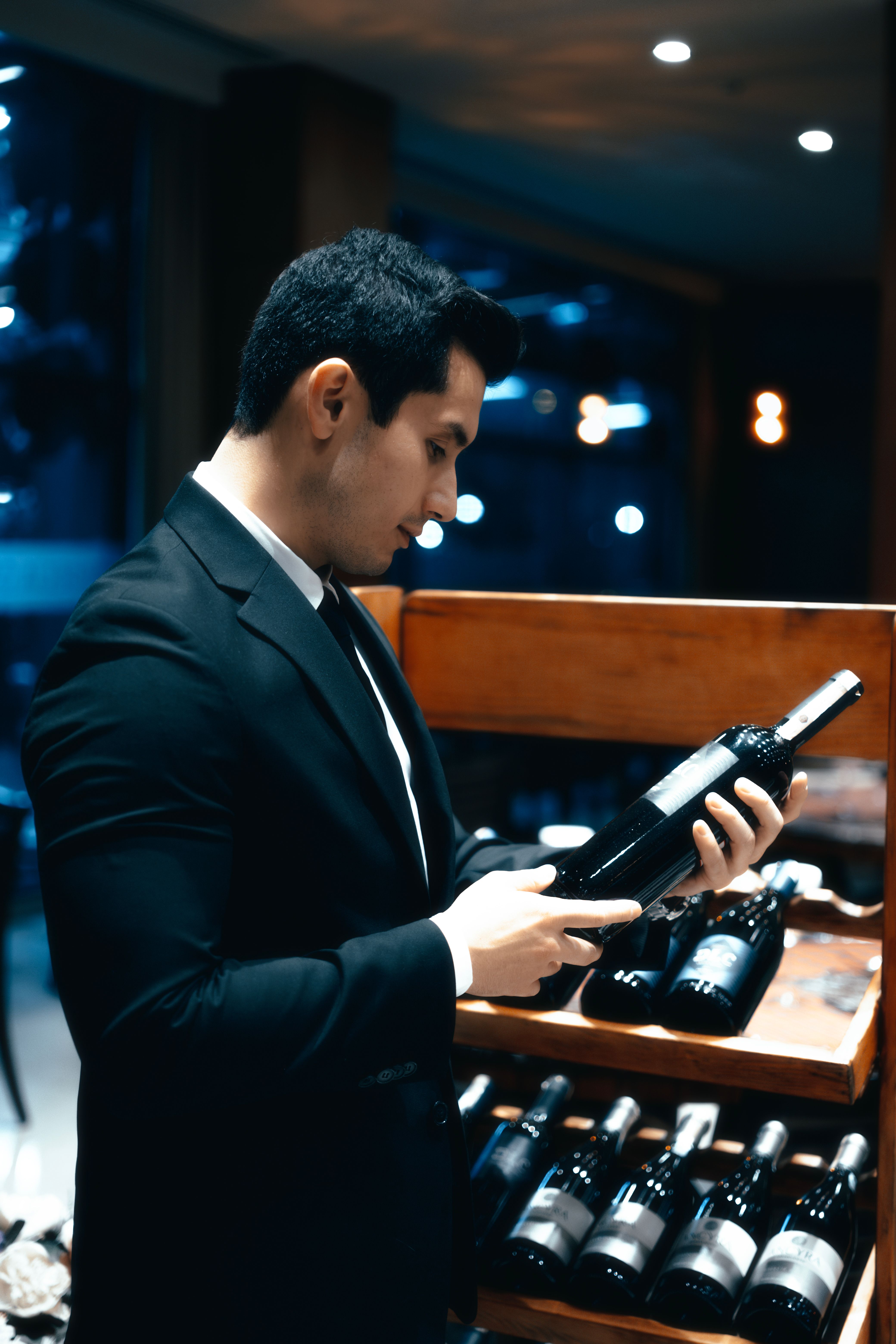 Man in Suit Selecting Wine Bottle in Elegant Store · Free Stock Photo